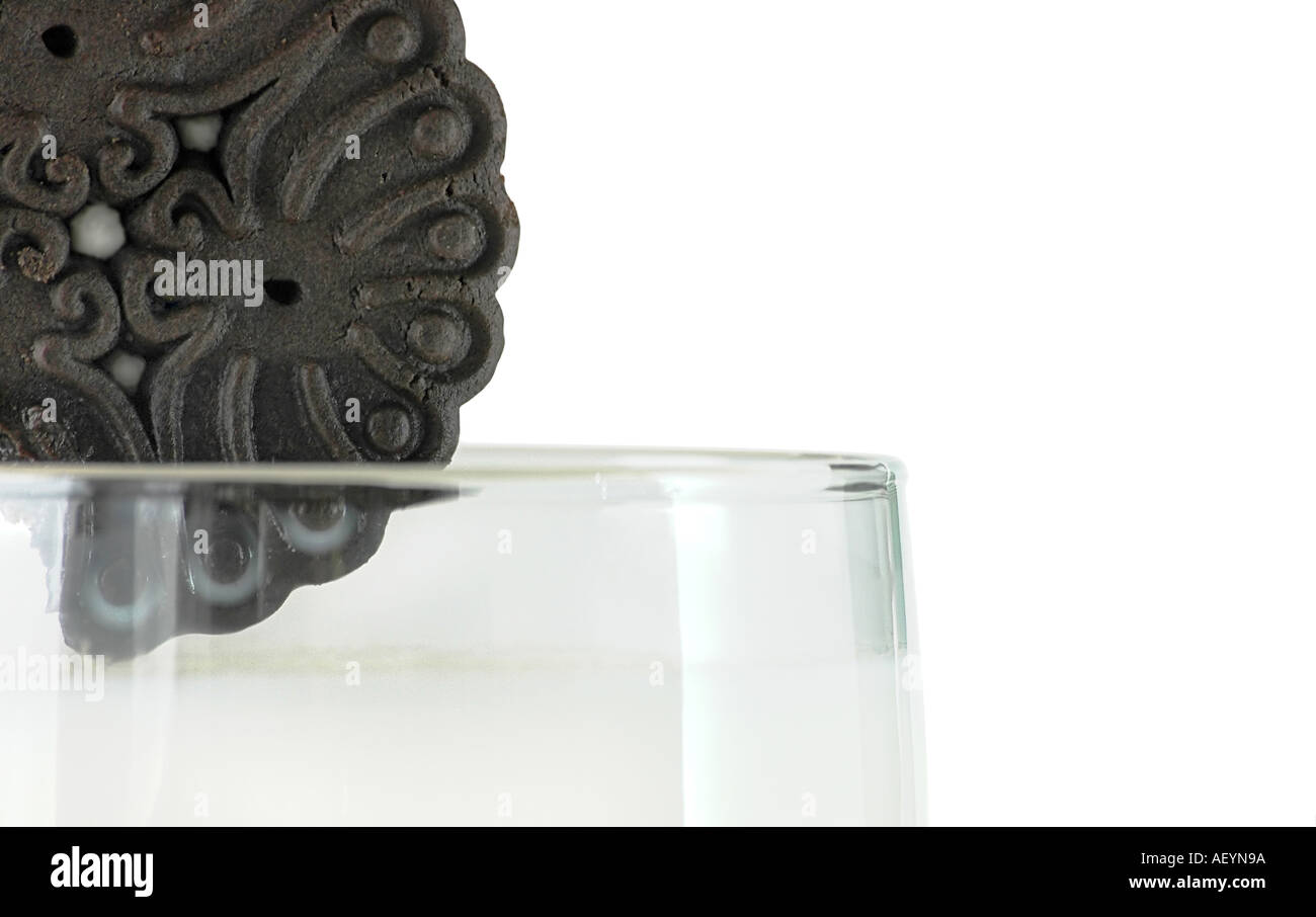A chocolate cookie is dunked in an ice cold glass of milk Stock Photo ...
