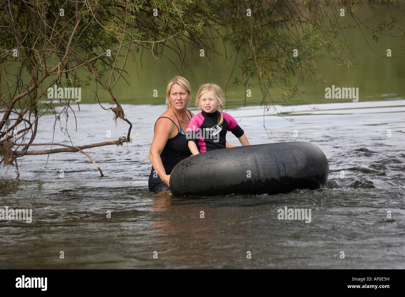Mother and young daughter playing with inflated rubber inner tube in ...