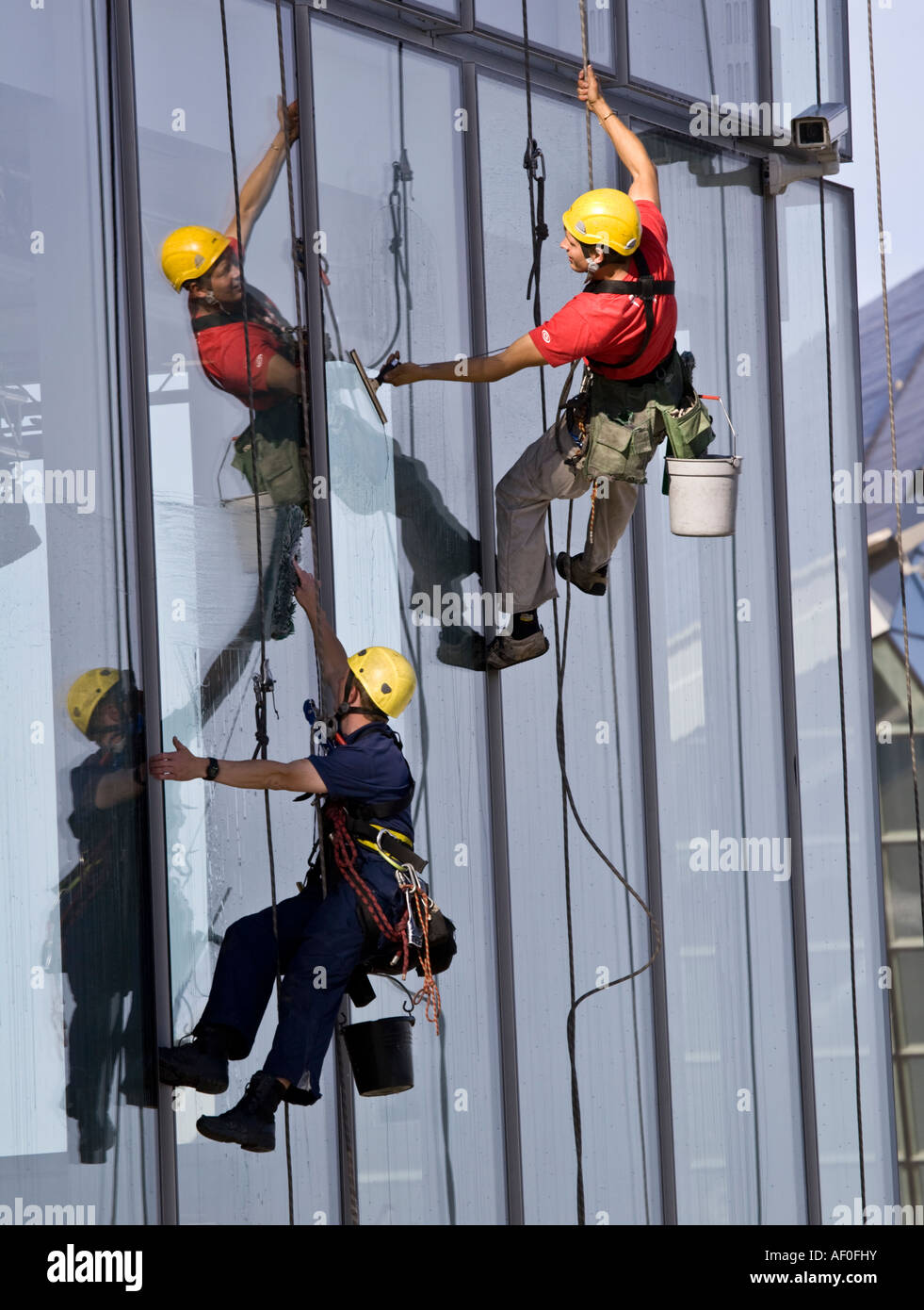 Window cleaners abseiling down a modern office block, Glasgow, Scotland ...