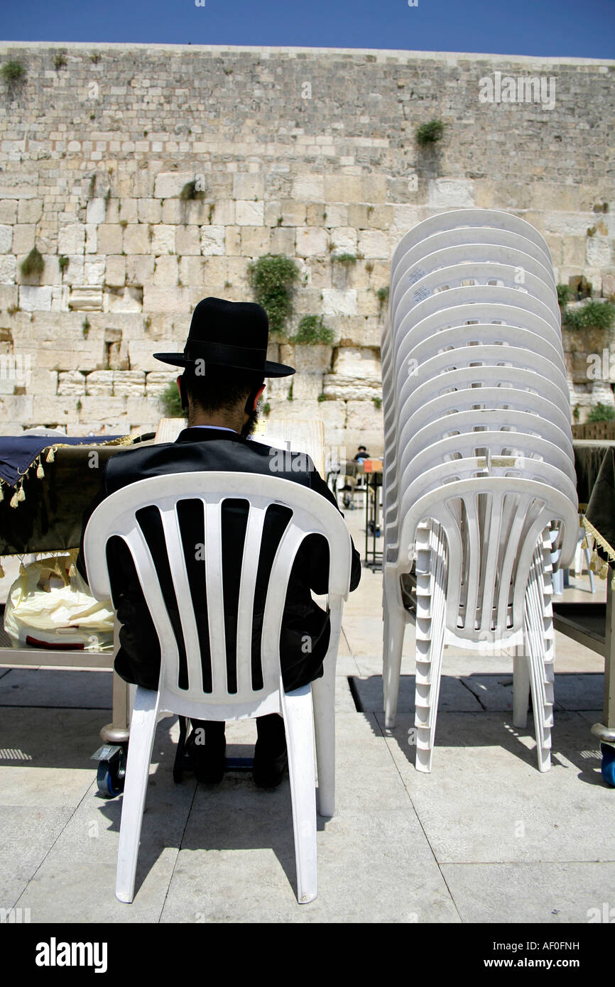 hasidic jew sitting reading the torah in between plastic chairs at the ...