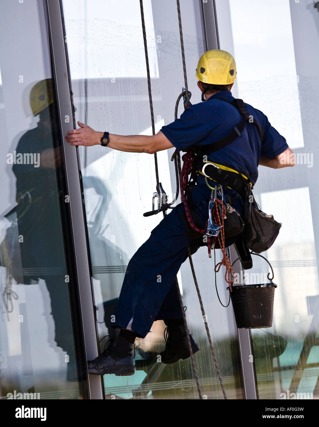 Window cleaner abseiling down a modern office block, Glasgow, Scotland ...