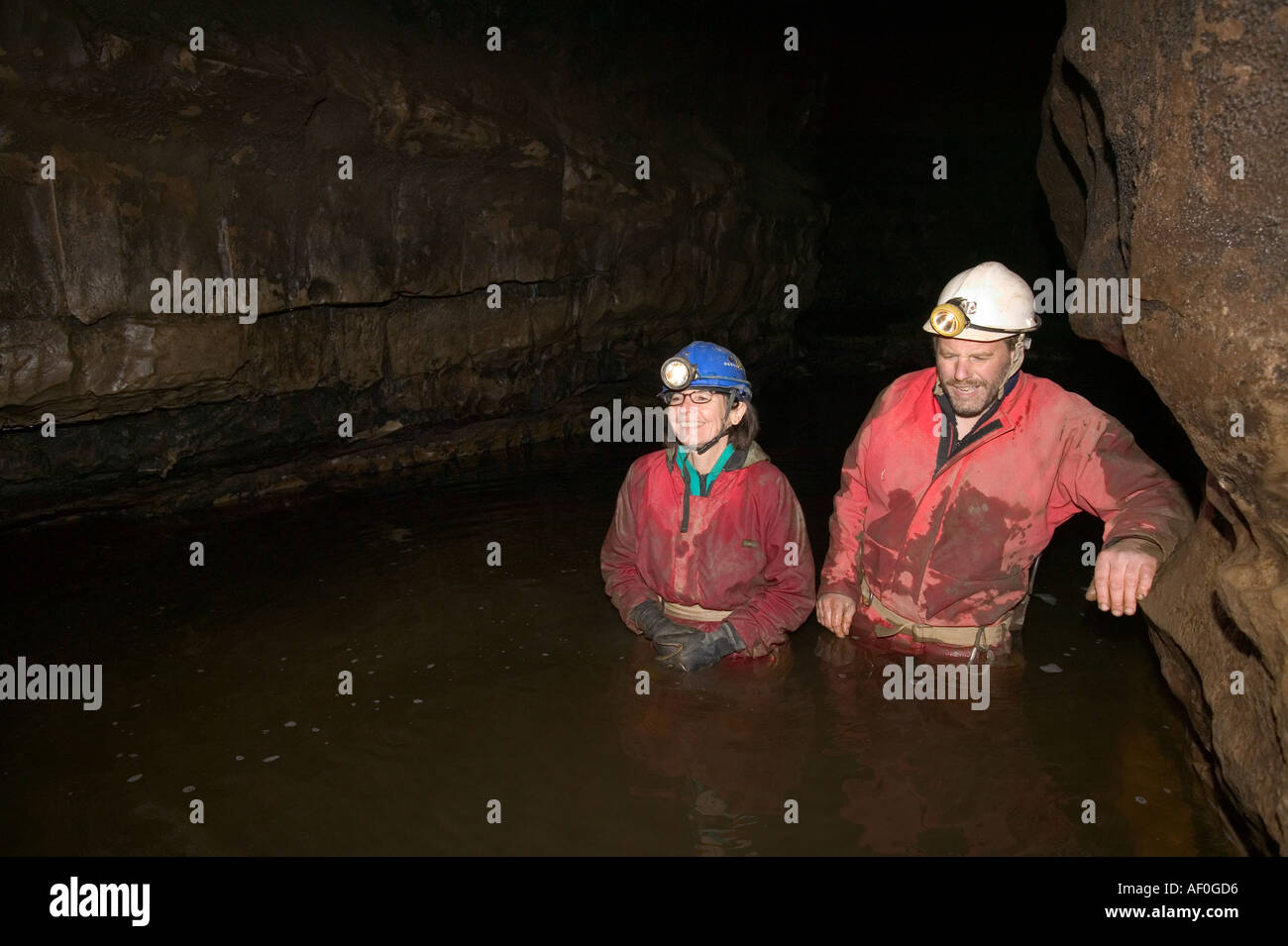 a male and female caver wade through a deep section of stream ...