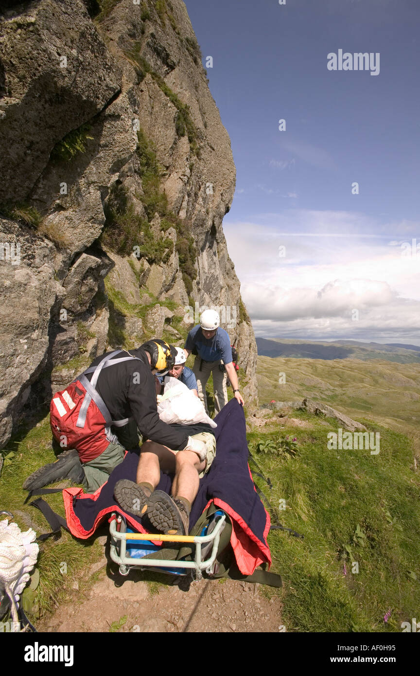 a mountain rescue team doctor helps a casualty onto a stretcher with a ...