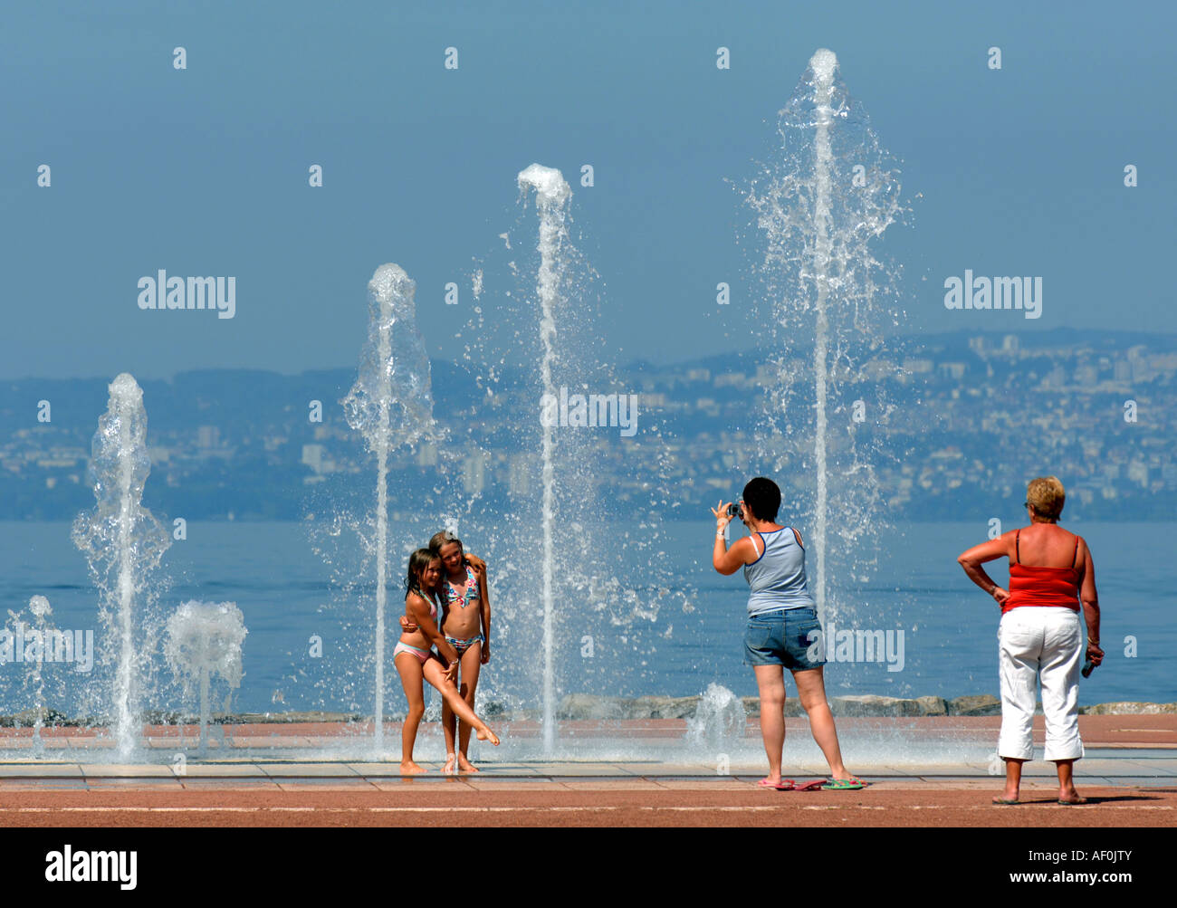 Evian, children playing in the water fountain at the side of Lake ...