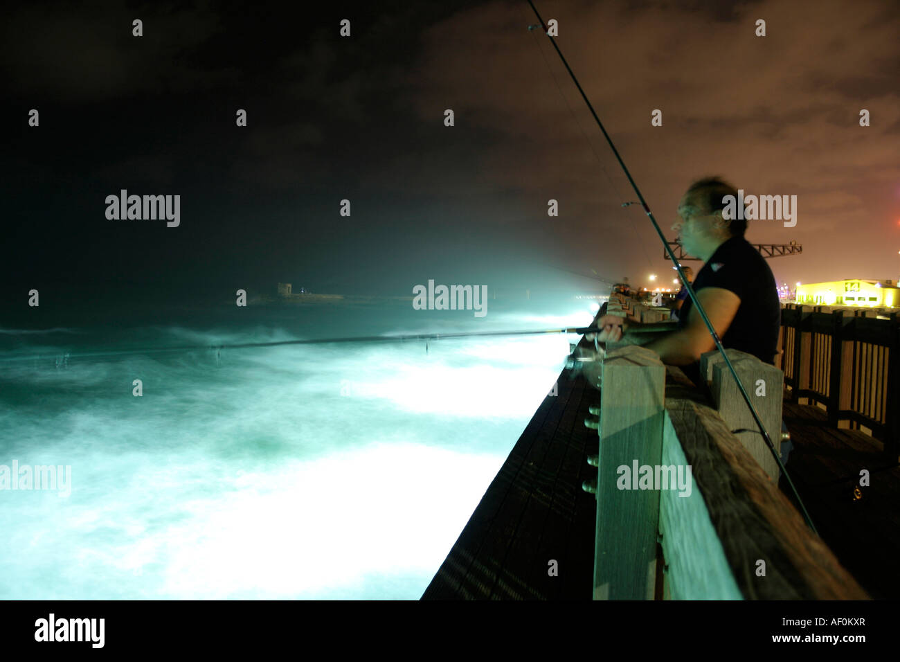 fisherman on pier by night Stock Photo - Alamy