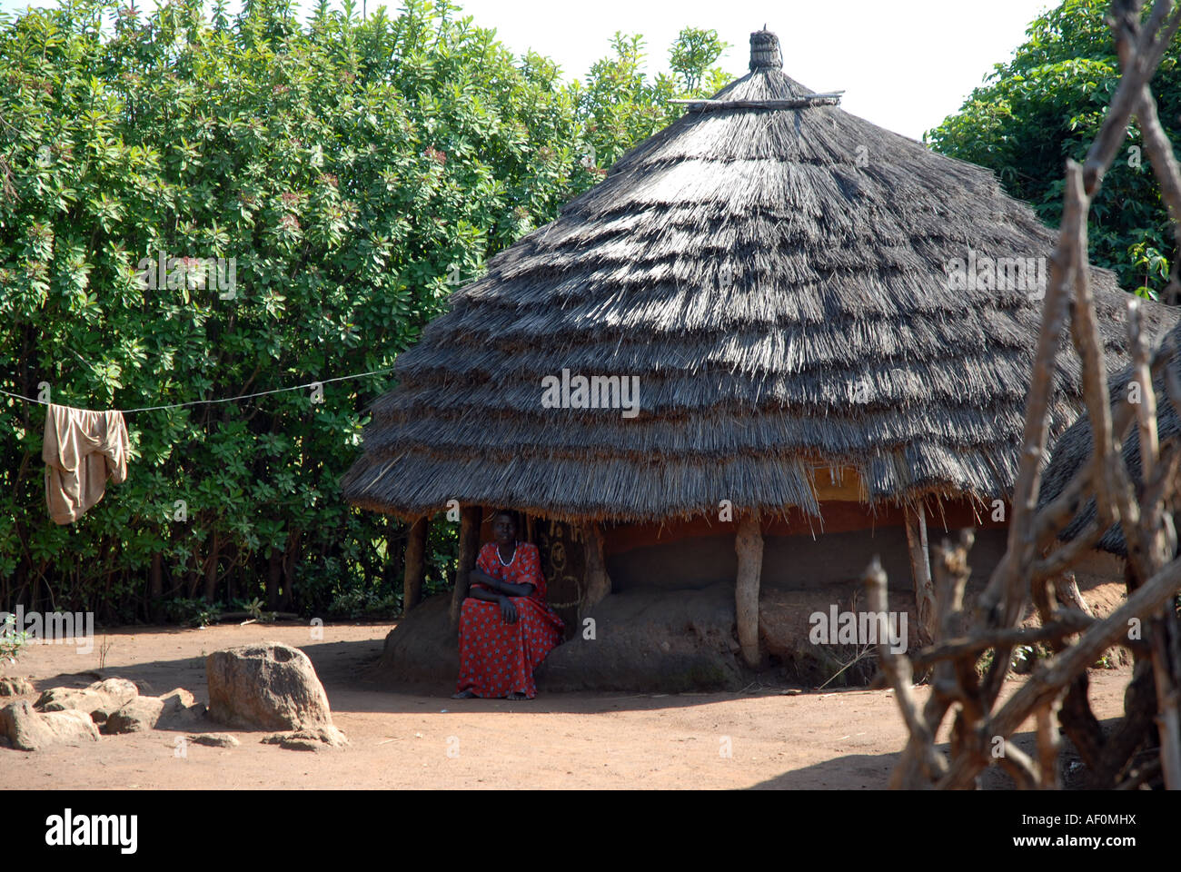 woman sitting on the threshold of her thatched village home, Loroukul ...