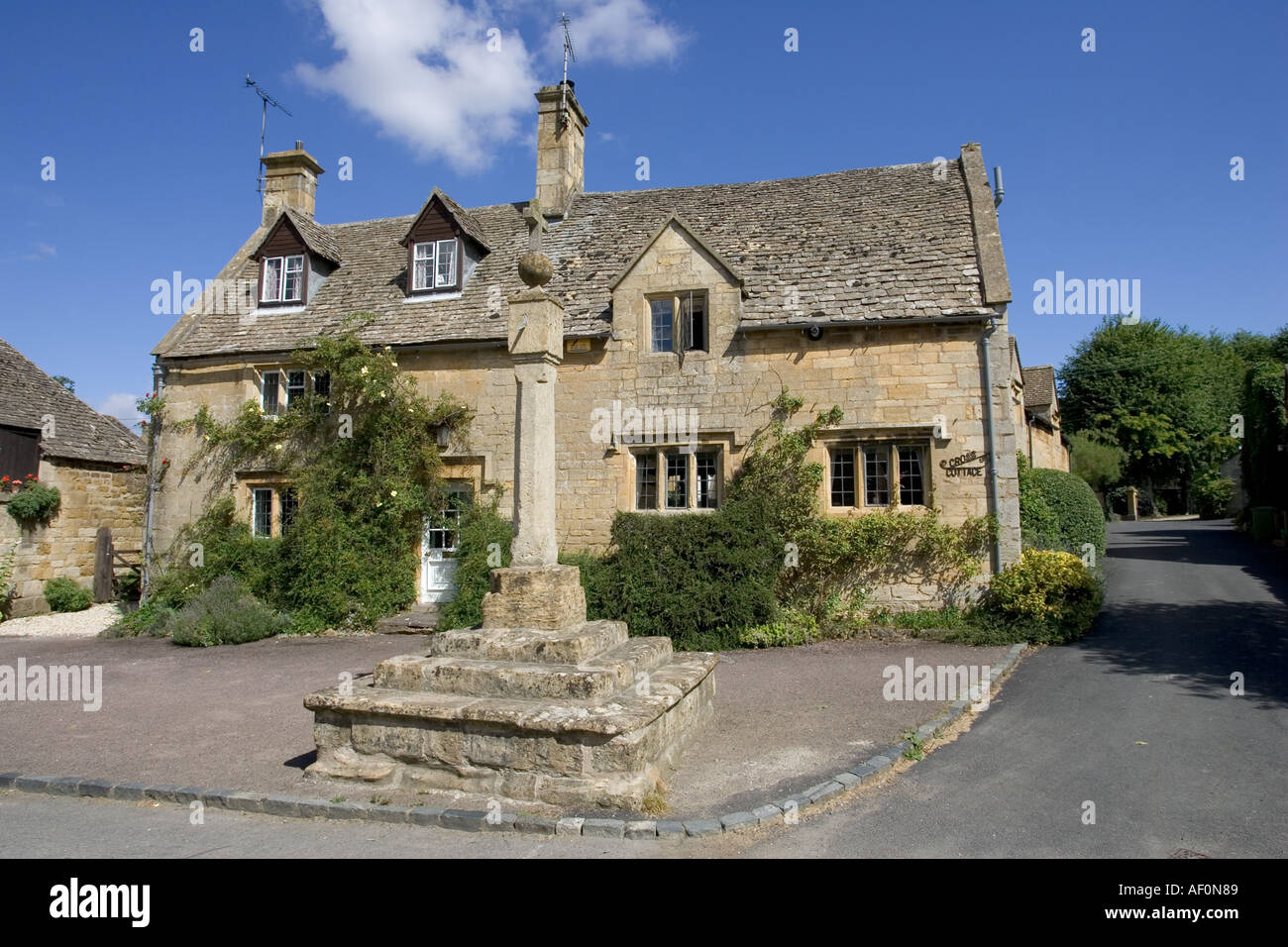 Cross Cottage with medieval cross outside village of Stanton Cotswolds ...