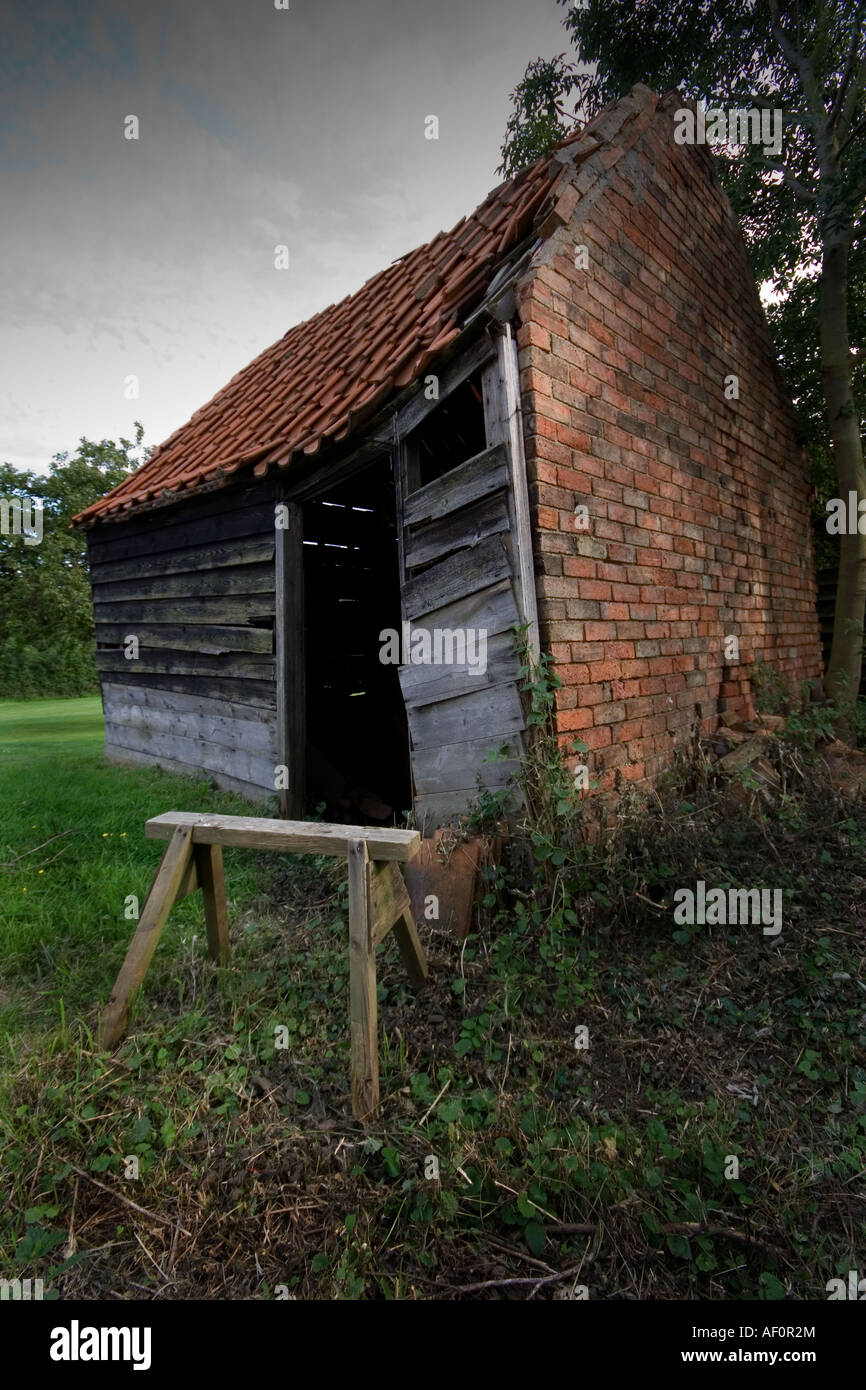 Old garden shed with decaying walls and roof, outside wooden cutting ...