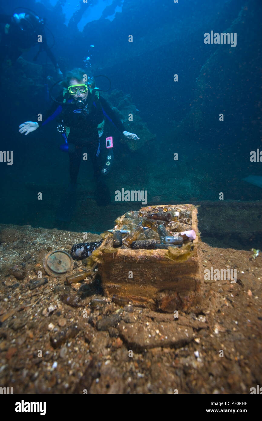 Scuba diver near box of glass bottles in cargo hold of sunken ship ...