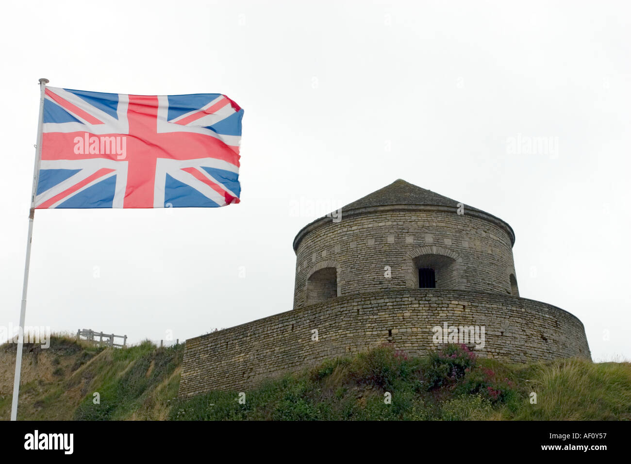 Union jack flag flies in a cloudy sky with a german gun emplacement in ...