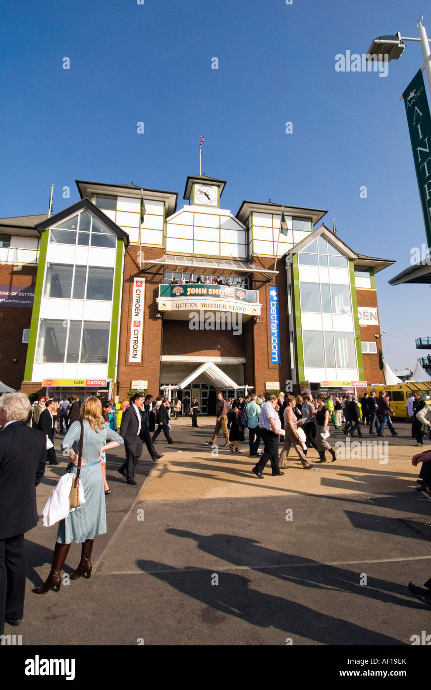 Crowd walking by Queen Mother stand on sunny day at Aintree race course ...