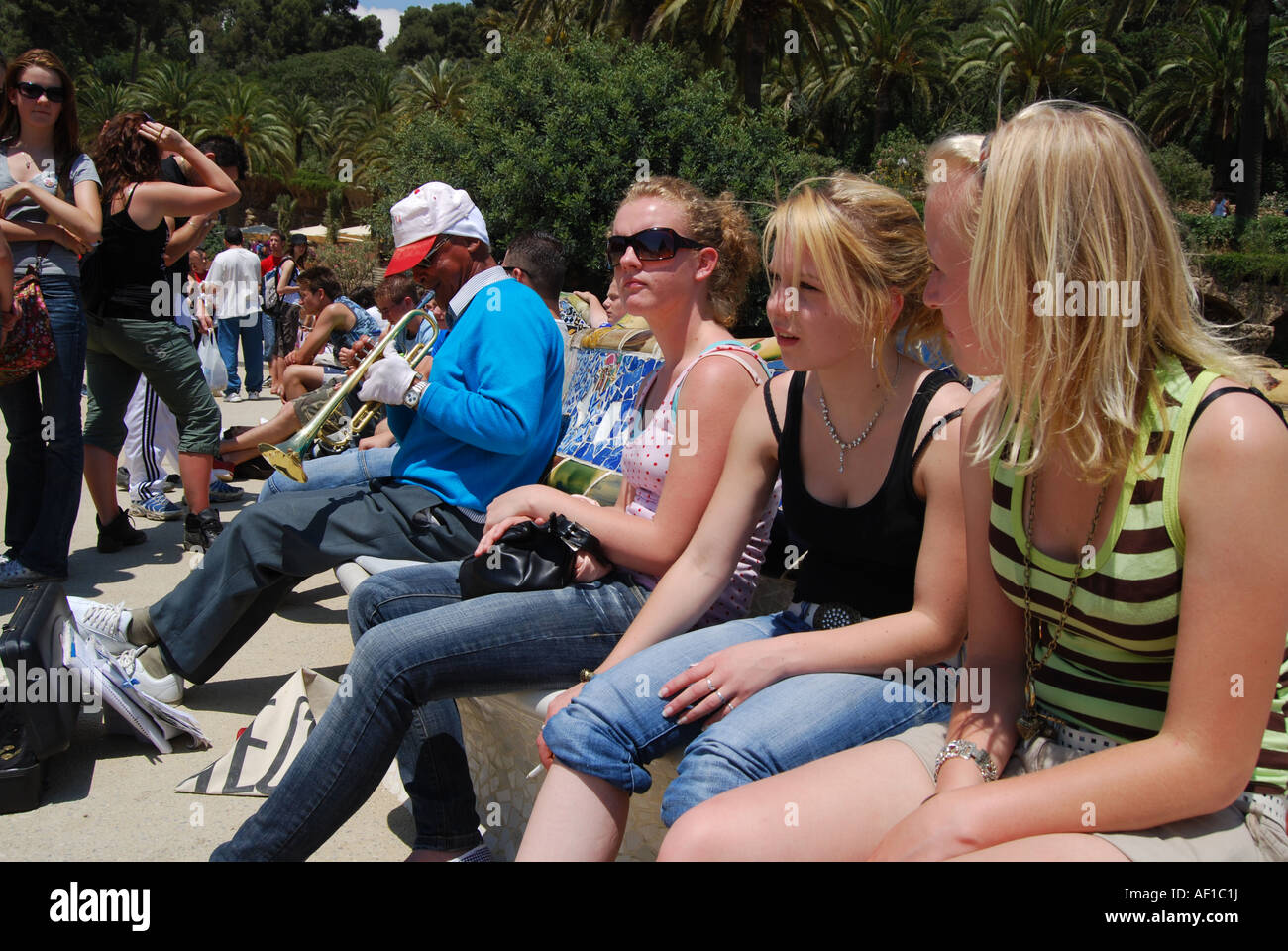 school group of teenagers with busker sitting on park benchs in Parc ...