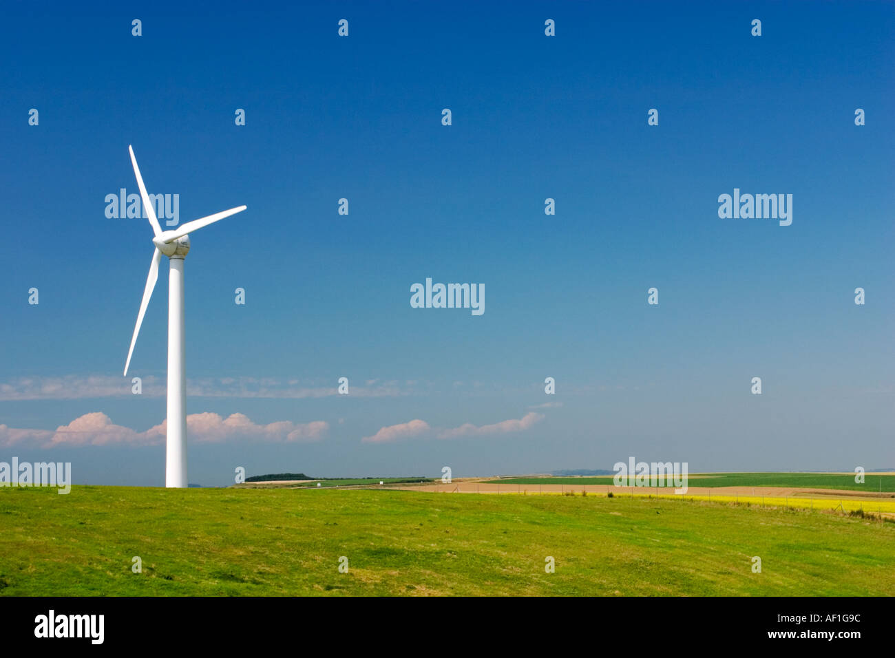 View of wind generator turbine against farming landscape with blue sky ...
