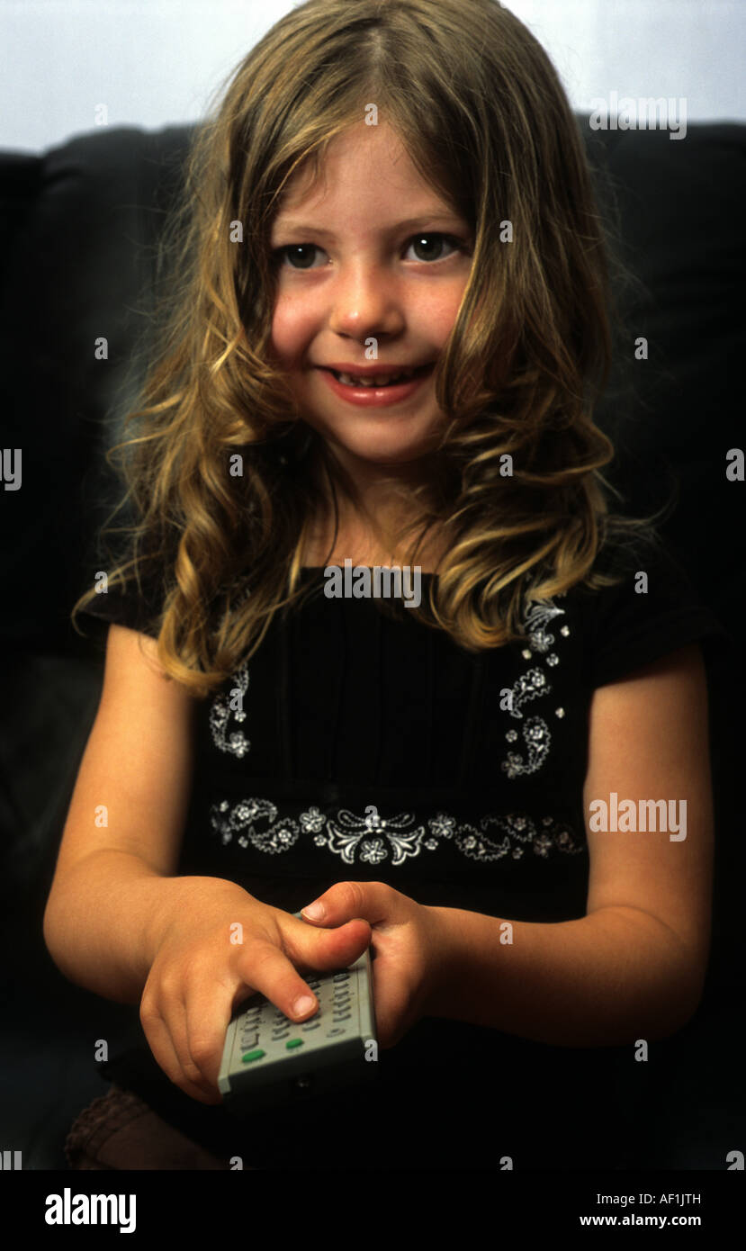 Young girl changing channels on a TV using a remote control at home ...