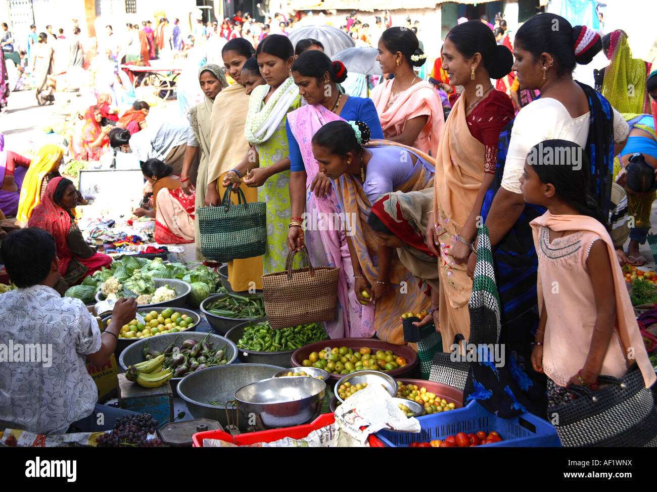 Group of Indian women crowding around busy market stall selling fruit ...