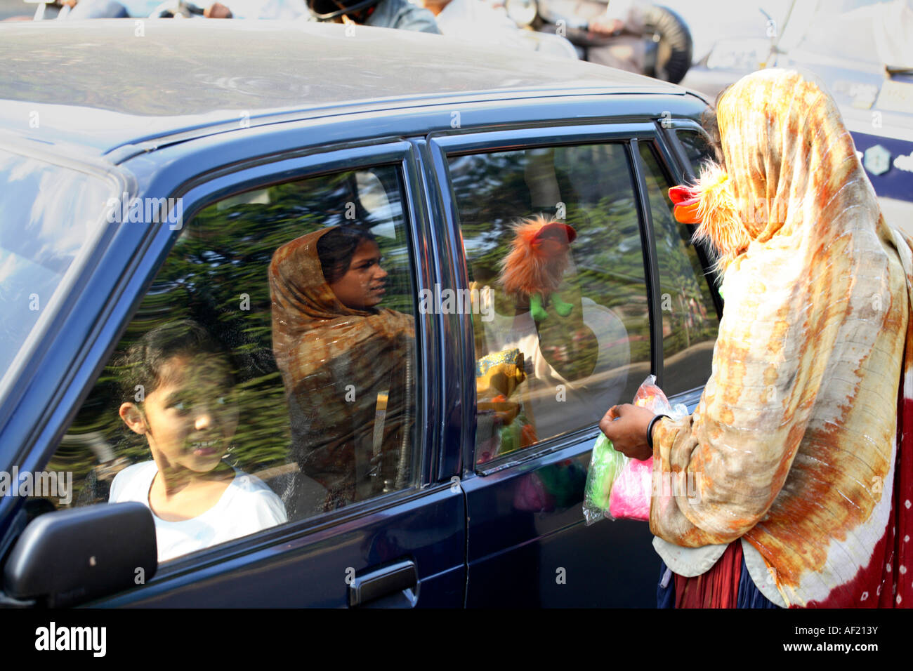 Young Indian girl holding up glove puppet to car window for sale in ...