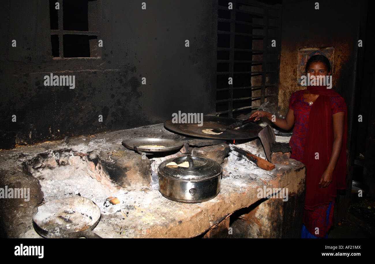 Young Indian female heating chapati on prehistoric stove in restaurant ...