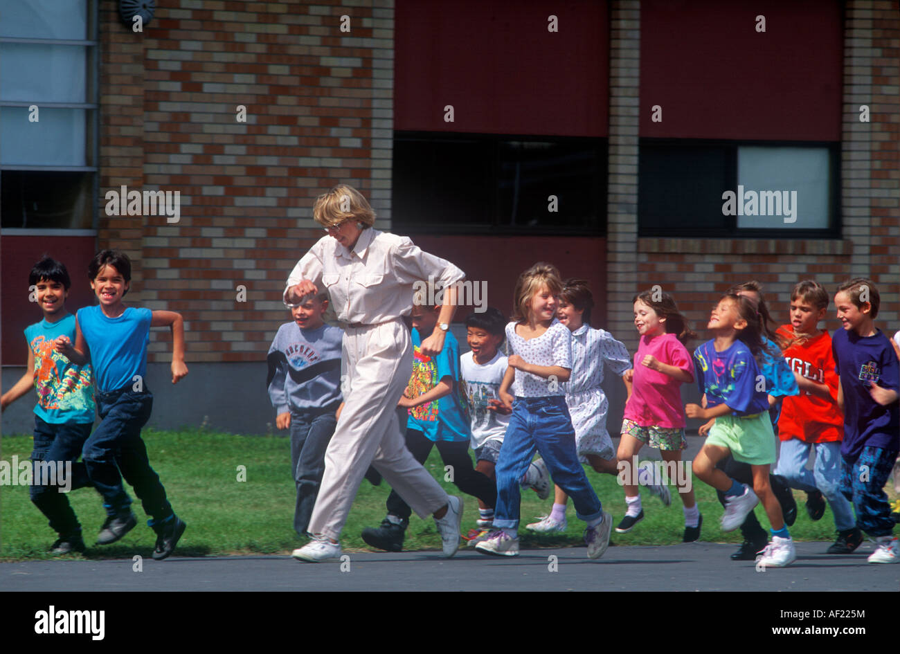 Elementary school teacher leads her class in physical exercise on ...