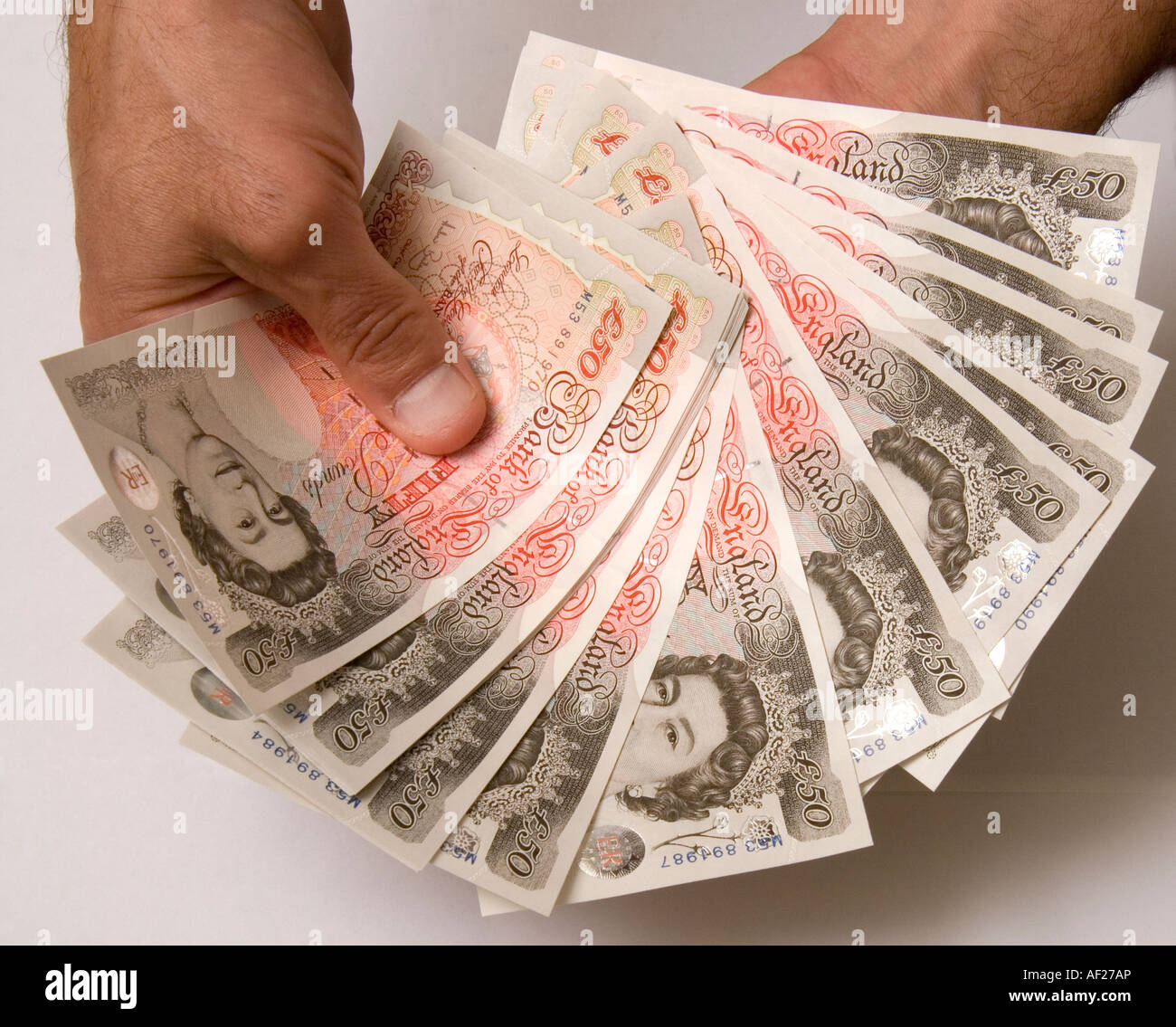 Mans Hands holding a fan of five hundred and fifty pounds in new fifty ...
