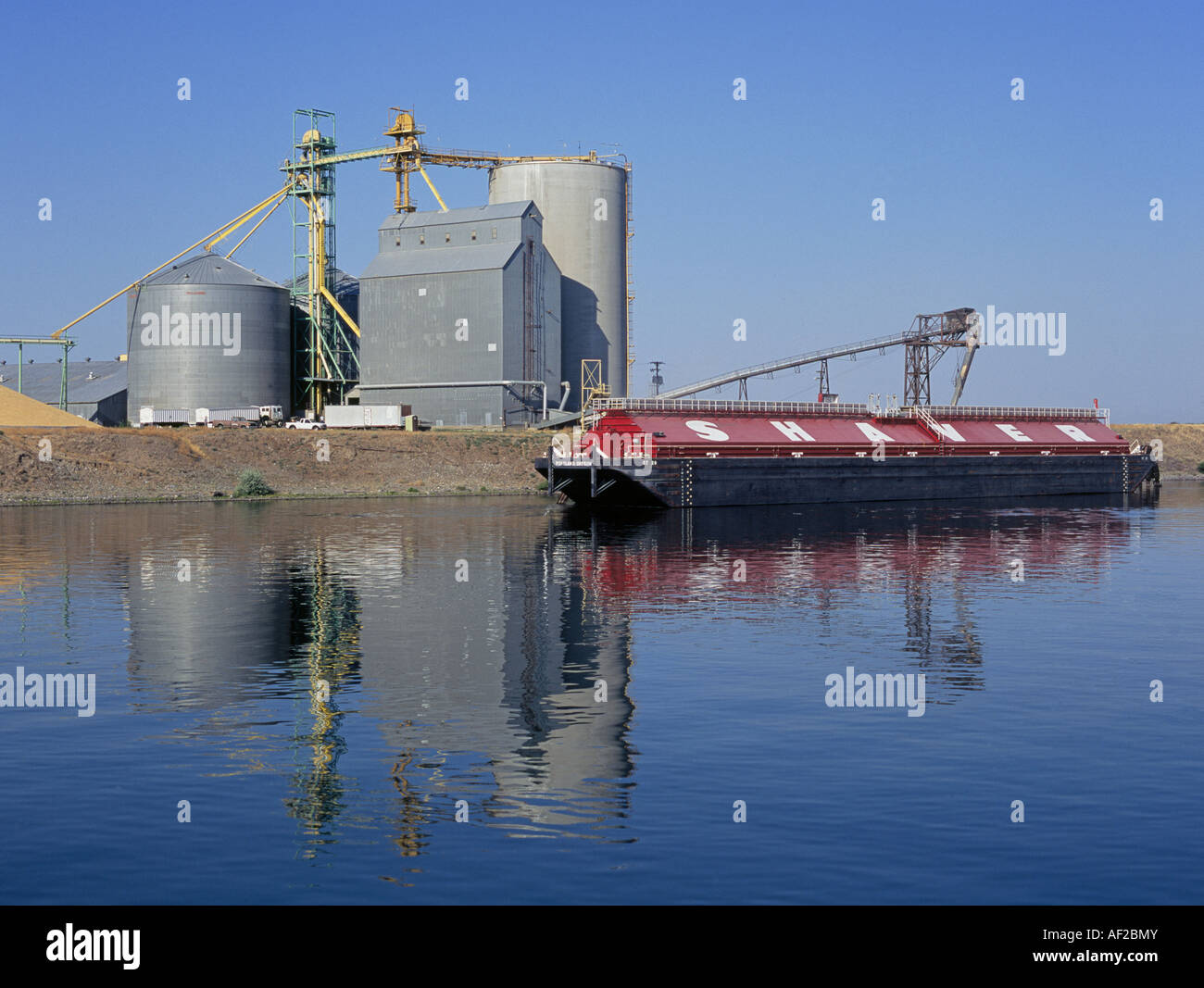 A grain barge and grain silos on the banks of the Columbia River Stock ...