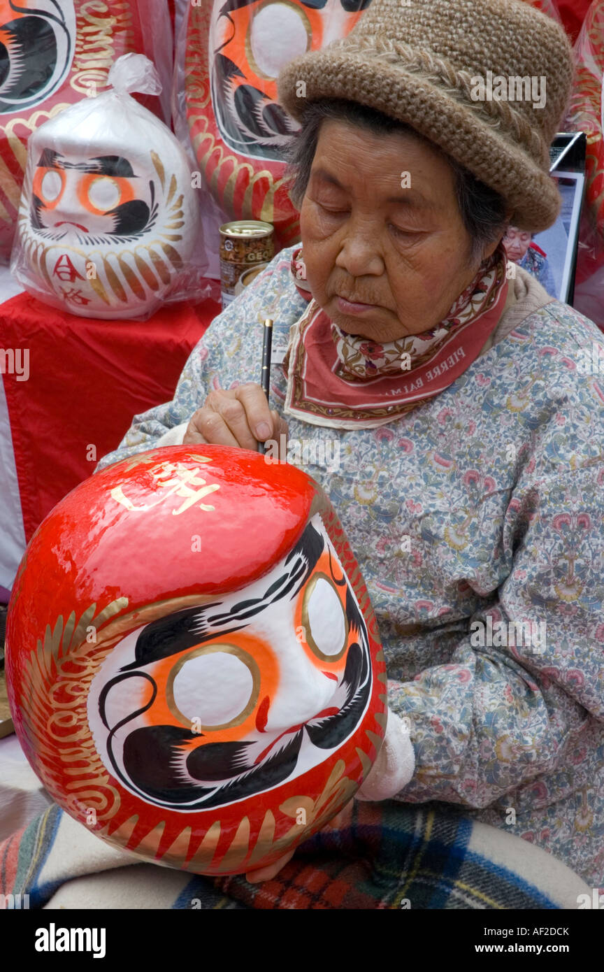 Elderly woman painting daruma dolls on sale at the Duruma Ichi Festival ...
