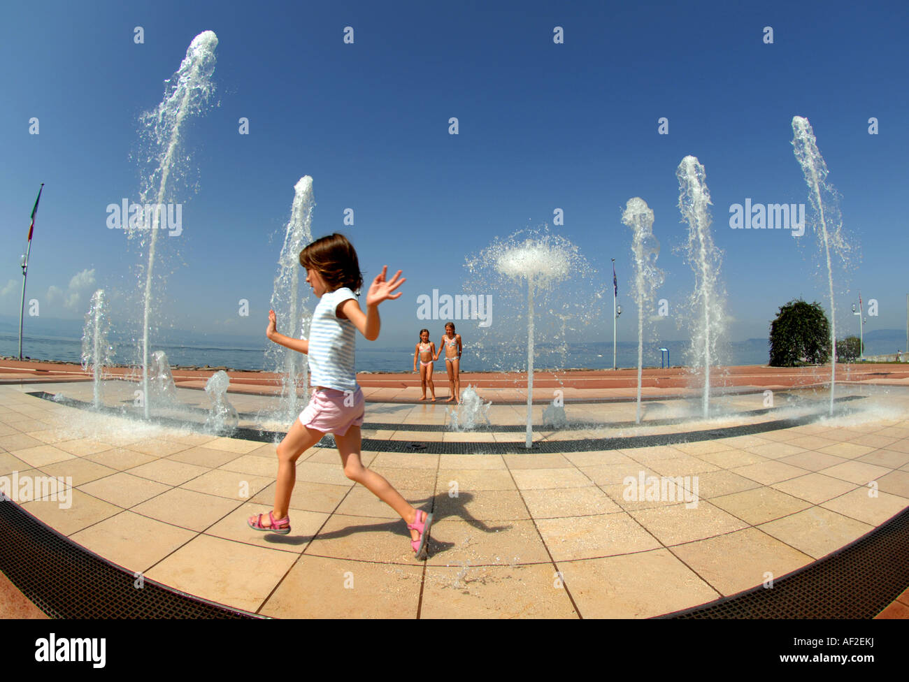 Evian, children playing in the water fountain at the side of Lake ...