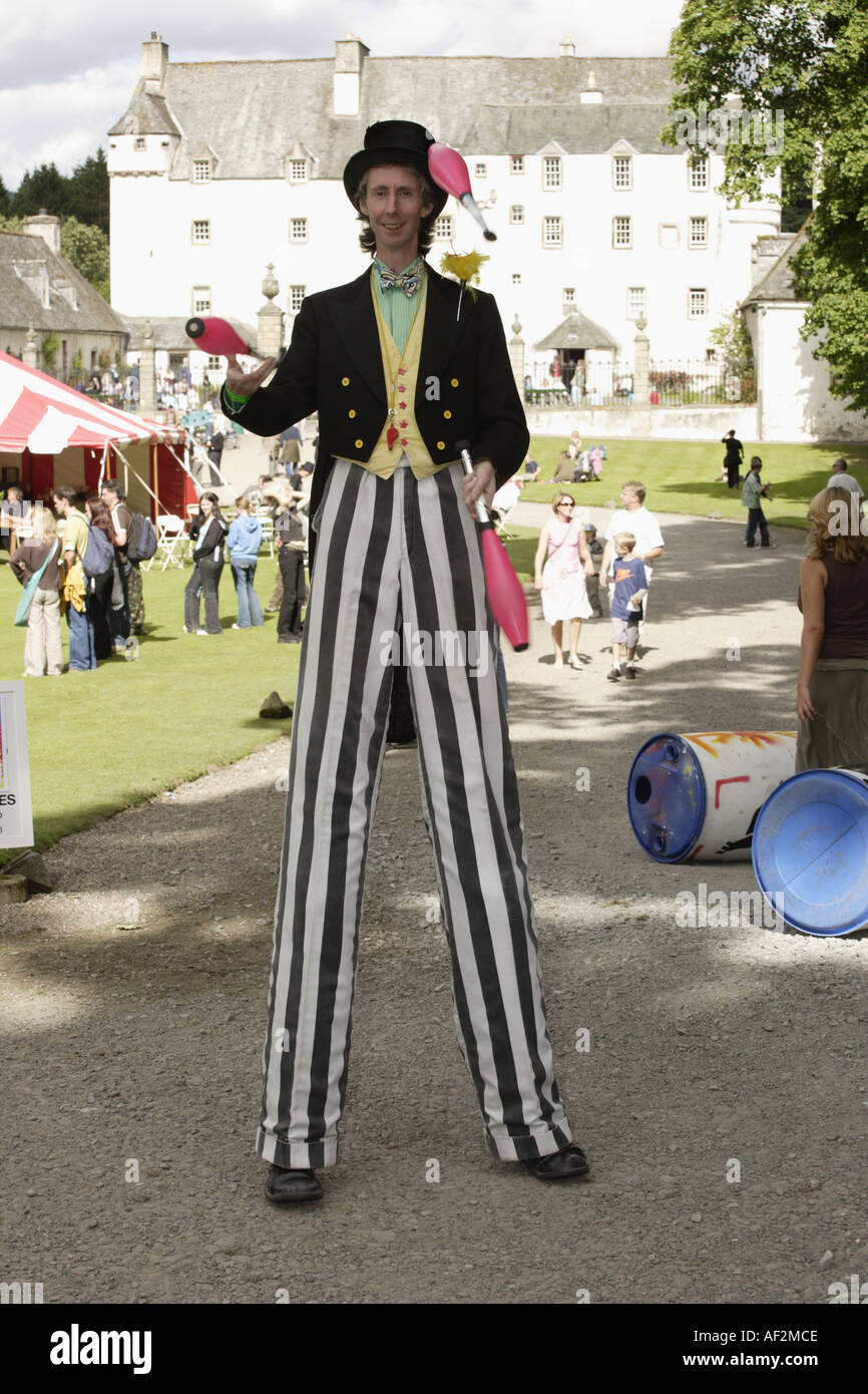 Traquair Fair juggler on stilts with Traquair House behind Stock Photo ...