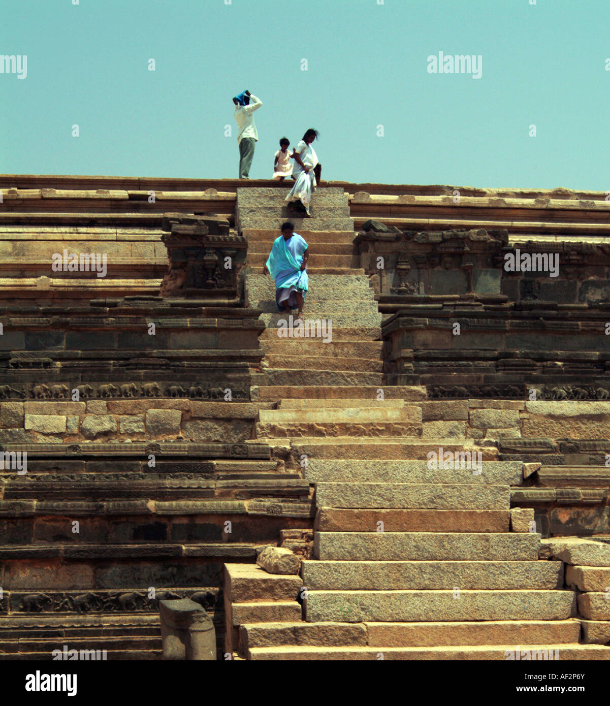 An Indian family descend the steps of a large temple structure in Hampi ...