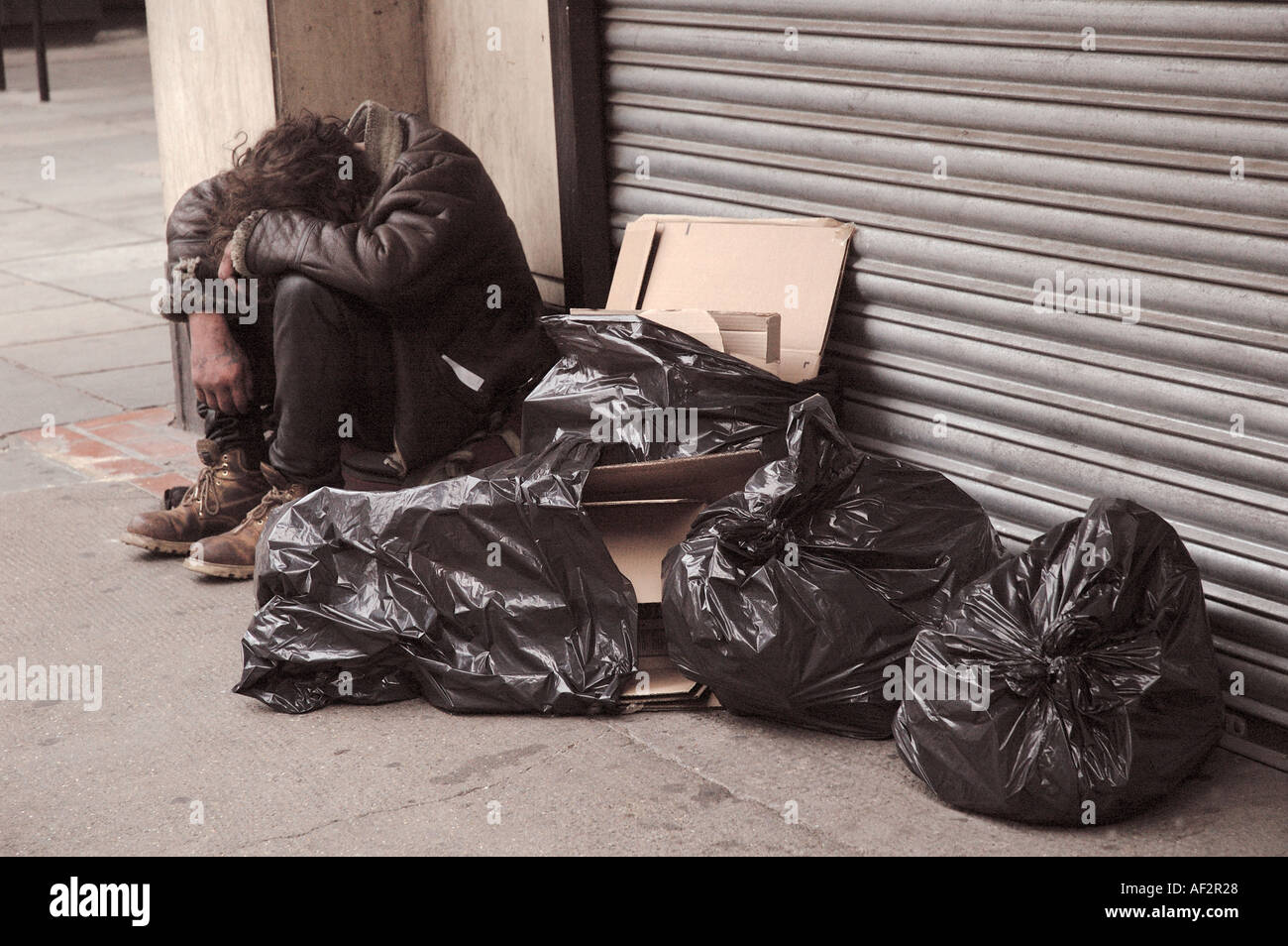 homeless man asleep next to garbage sack in London street Stock Photo ...