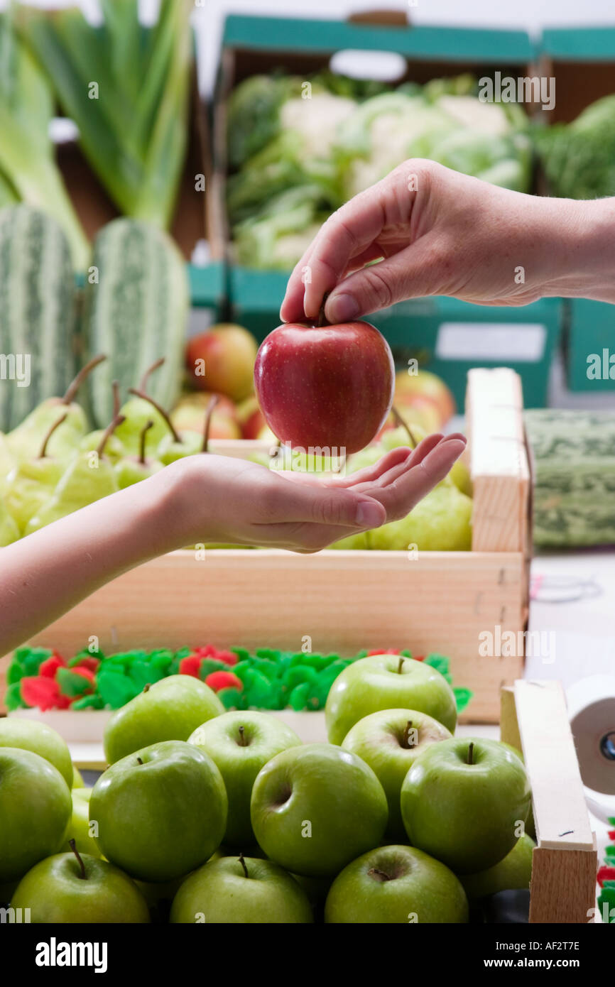 RED APPLE AND TWO HANDS WITH FRUIT AND VEGETABLES IN BACKGROUND UK ...
