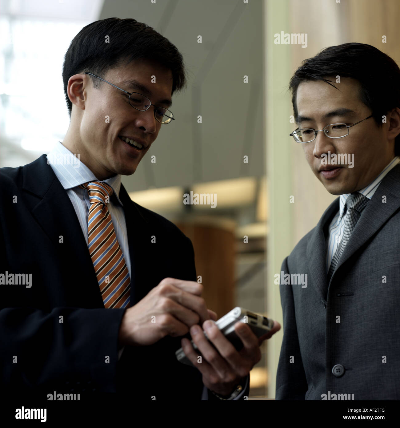Two business people consulting PDA together Stock Photo - Alamy