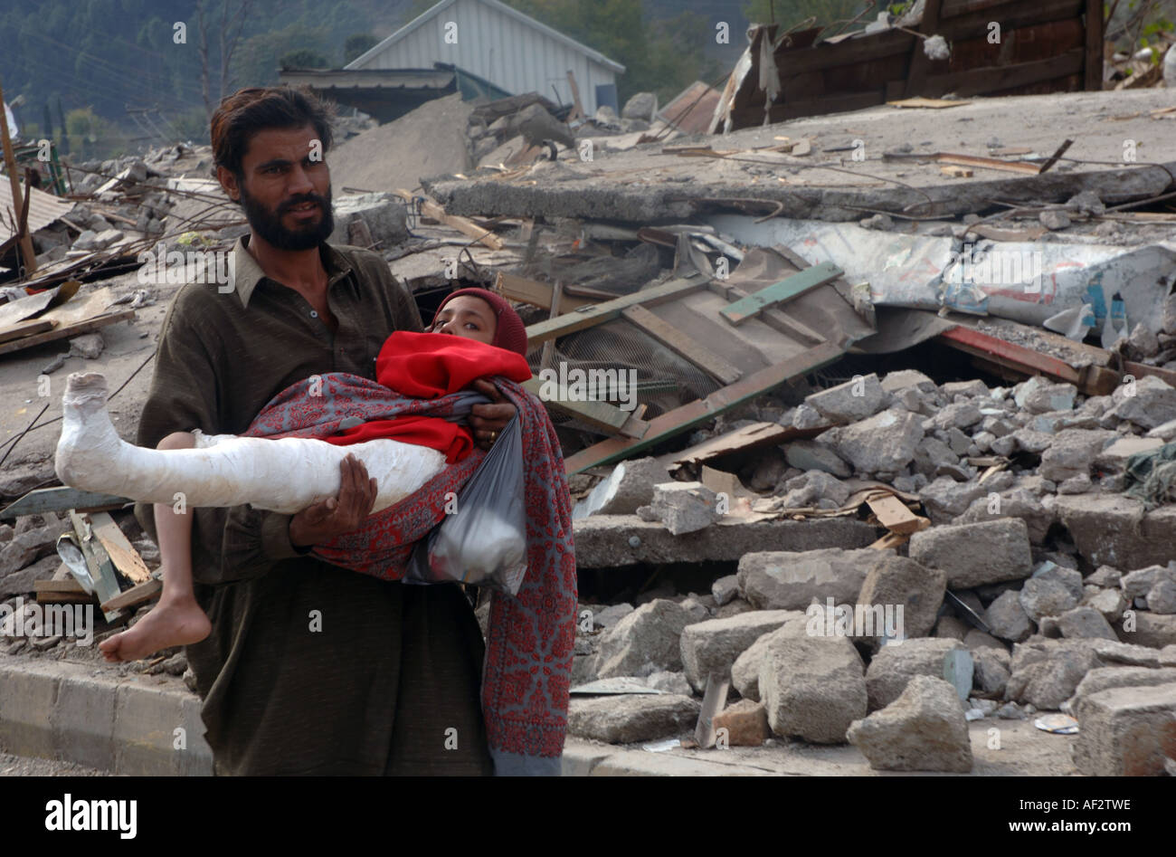 A father carries his injured daughter through Balakot after a 7.6 ...