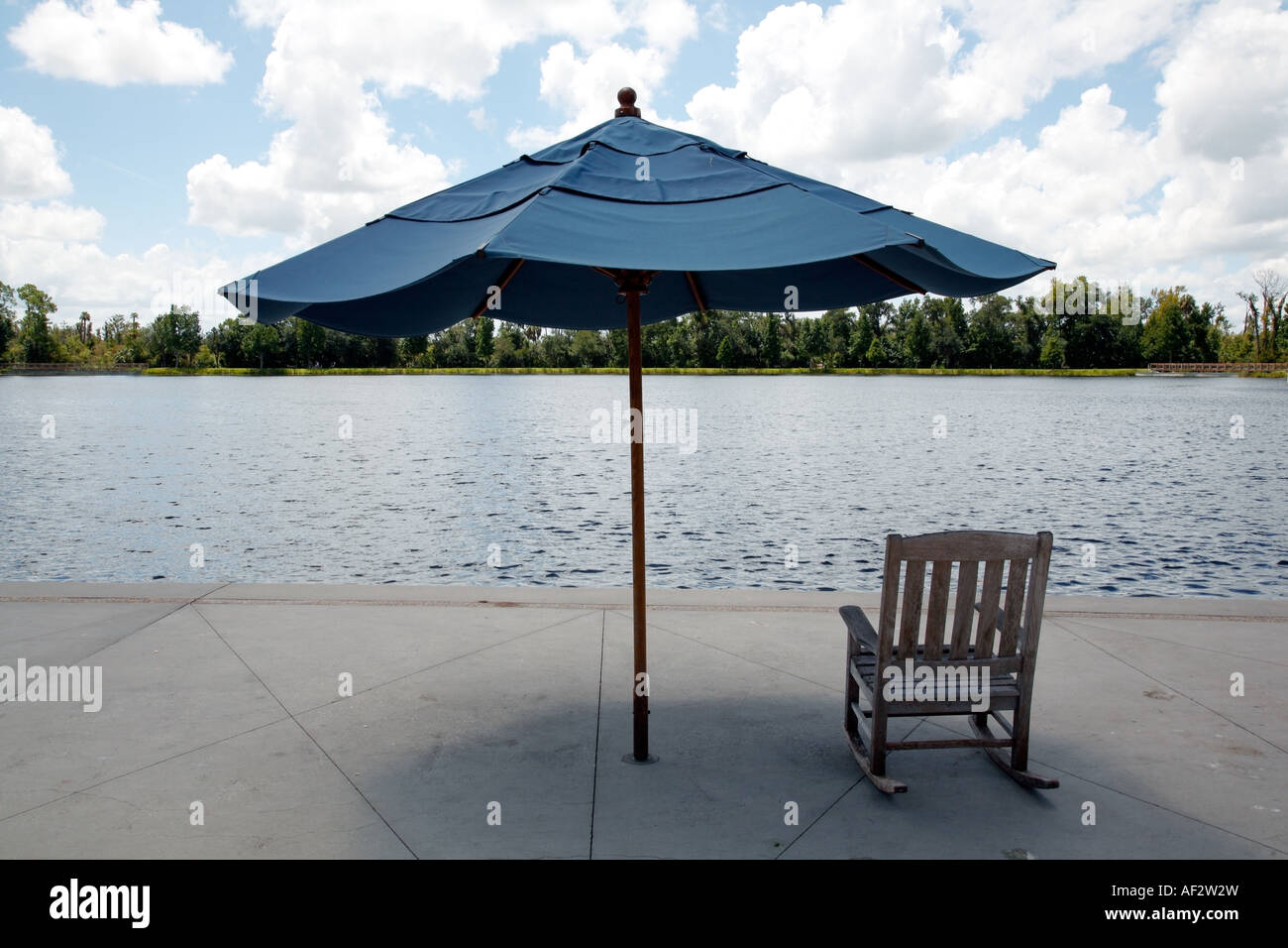 Parasol and empty wooden chair overlooking a lake Stock Photo - Alamy