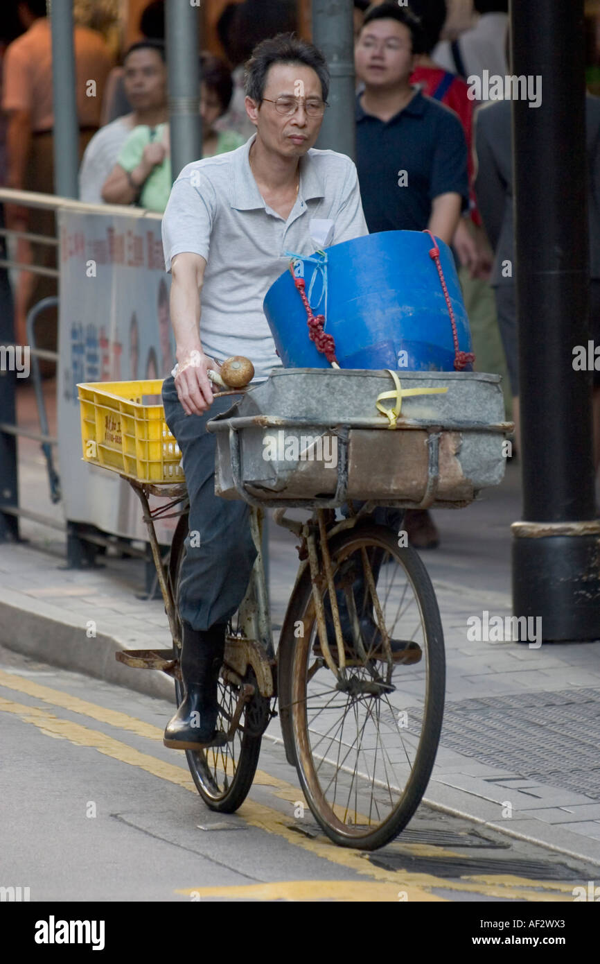 Fish delivery man pedaling bicycle down road with bucket on front ...