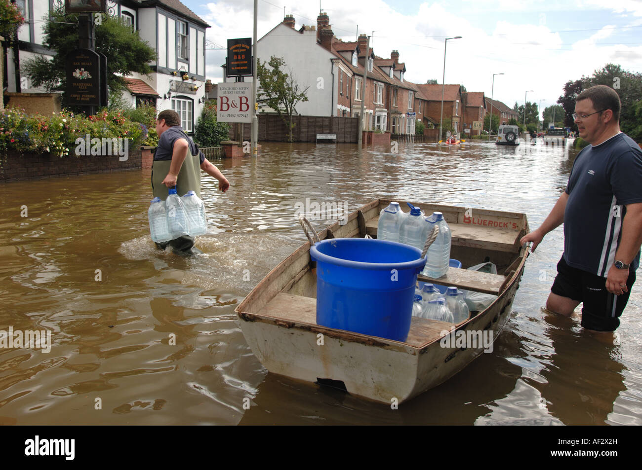People carrying bottled water in flooded Road in Longford area of ...