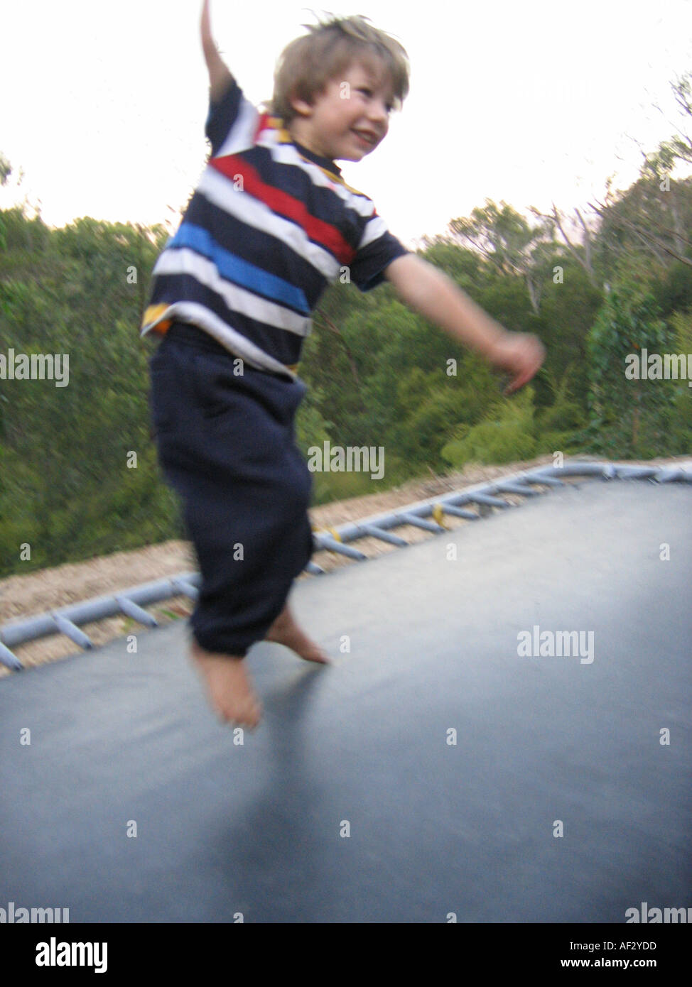 Young boy jumping on trampoline Stock Photo - Alamy