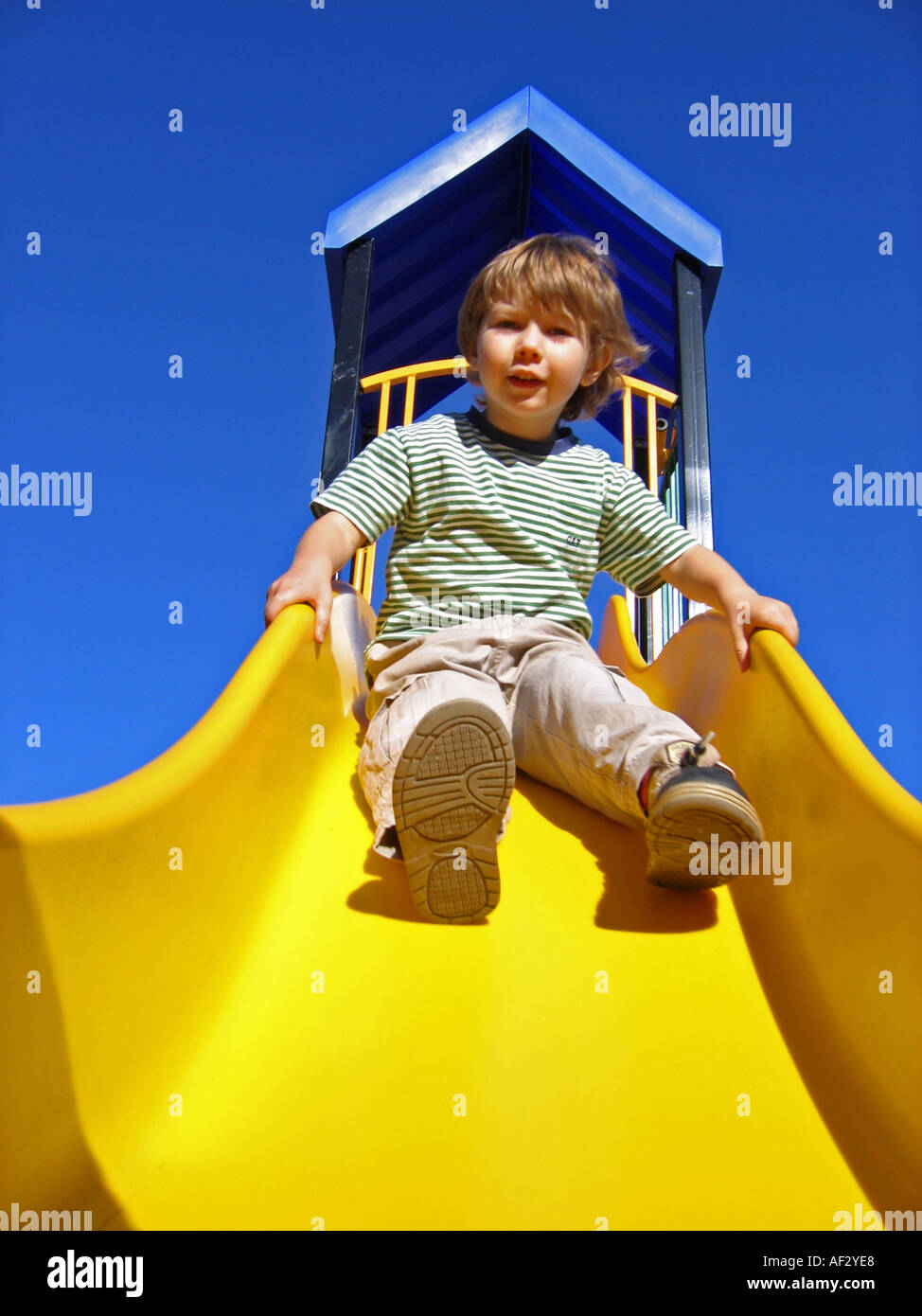 Young boy going down a slide in a park Stock Photo - Alamy
