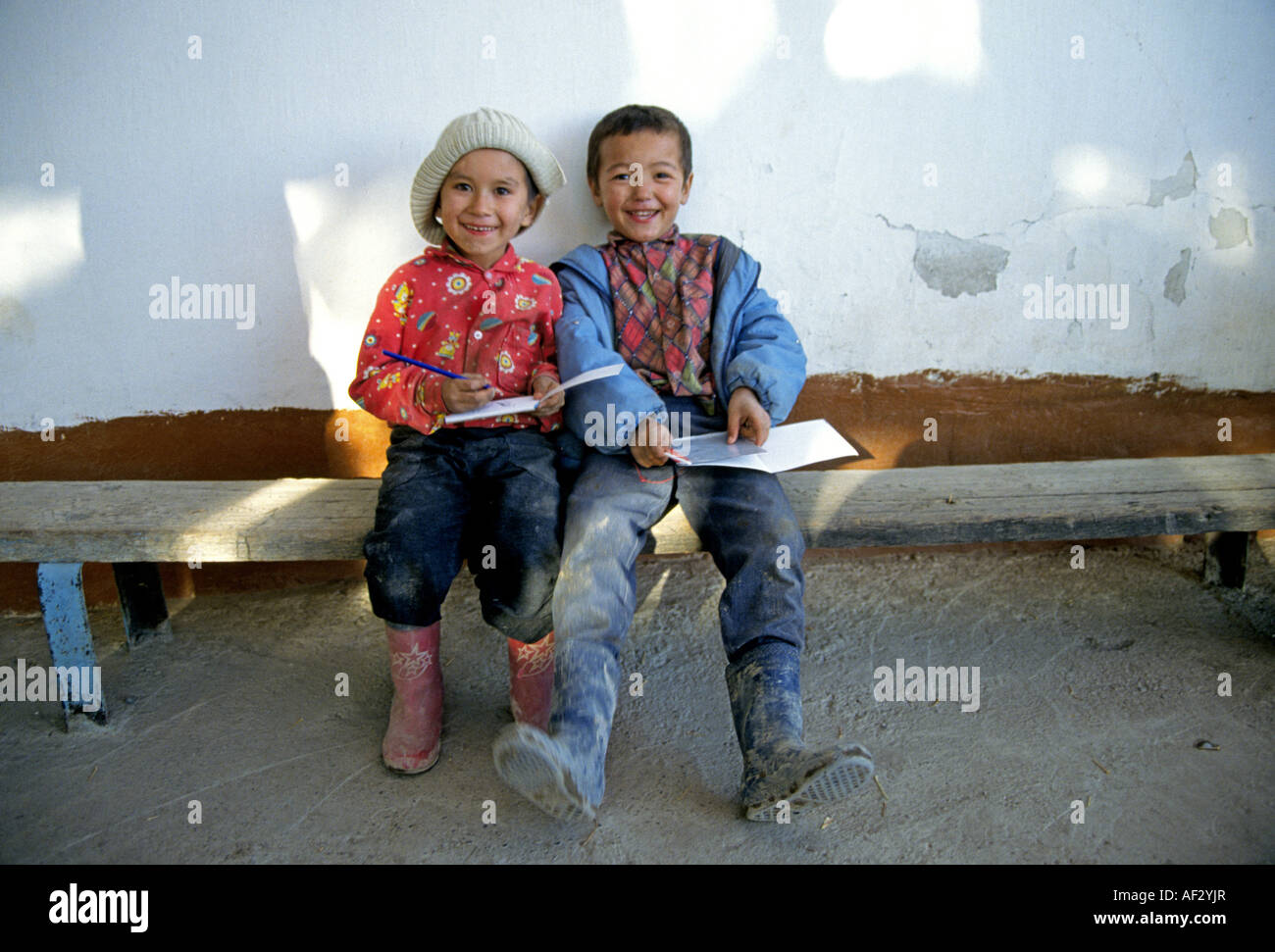 Two school children do their homework in a garden in a small mountain ...