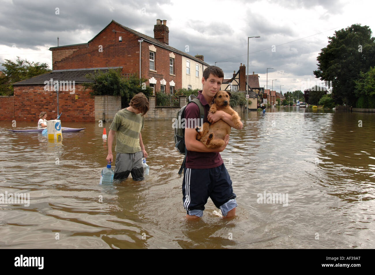 Two Boys with doga and drinknig water wade through floods in the ...