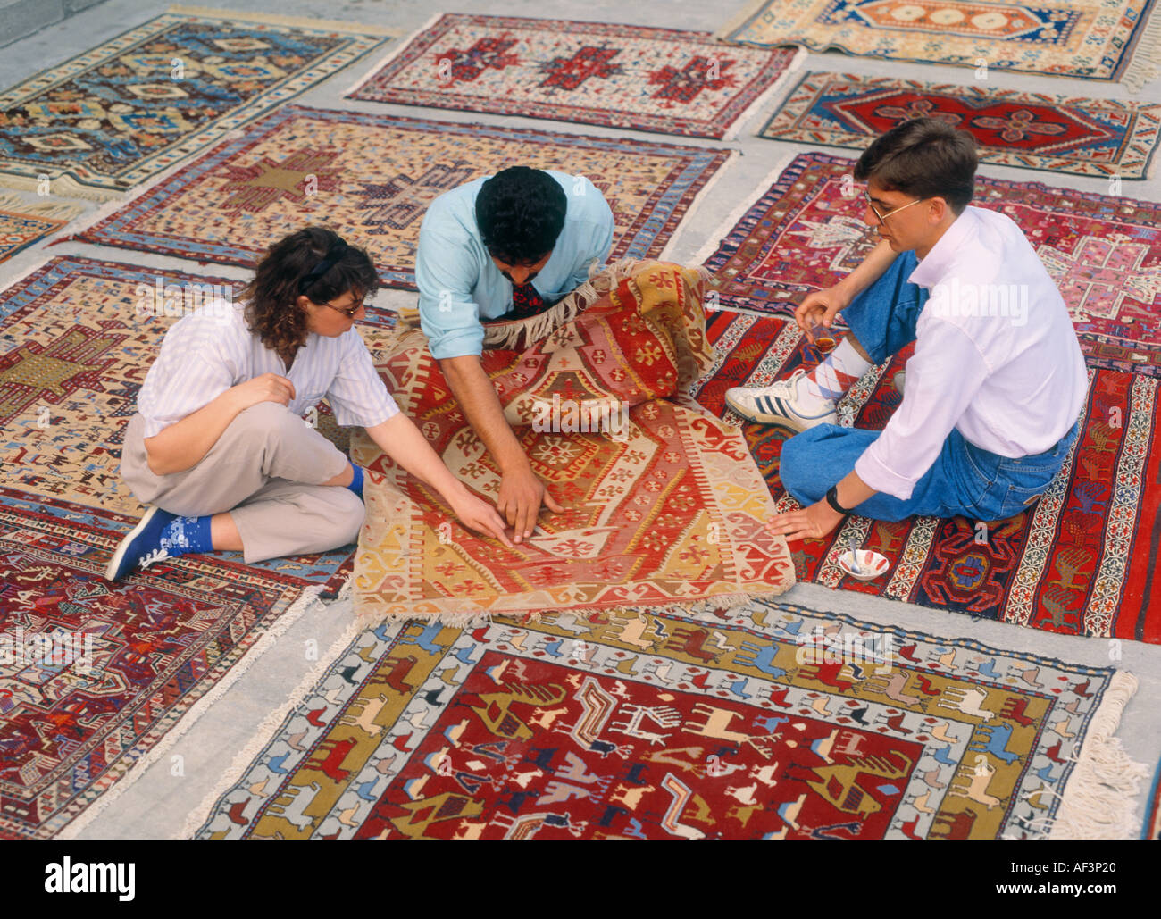 Istanbul Turkey Carpet seller demonstrating wares to tourist couple ...