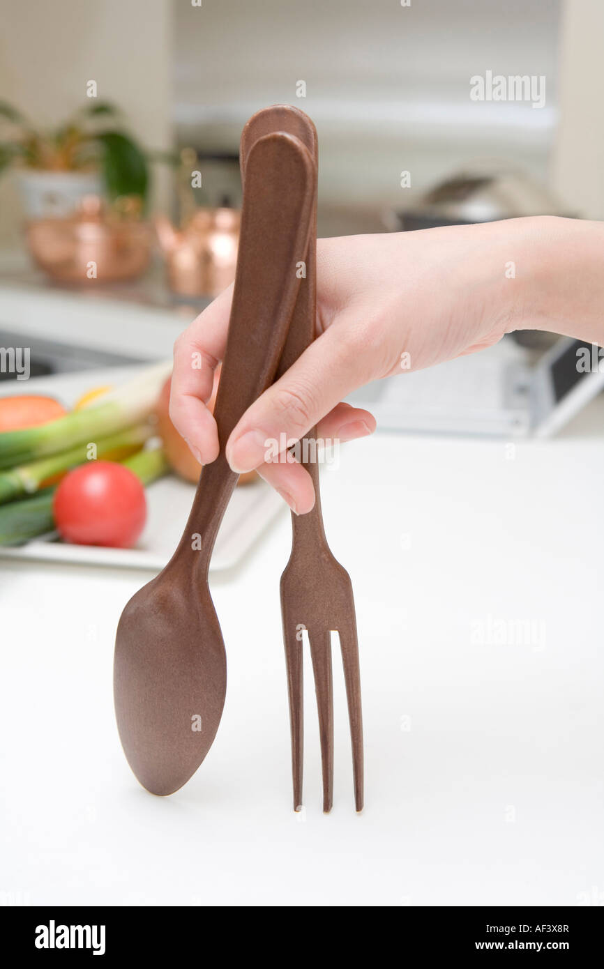 A hand holding a spoon and a fork Stock Photo - Alamy