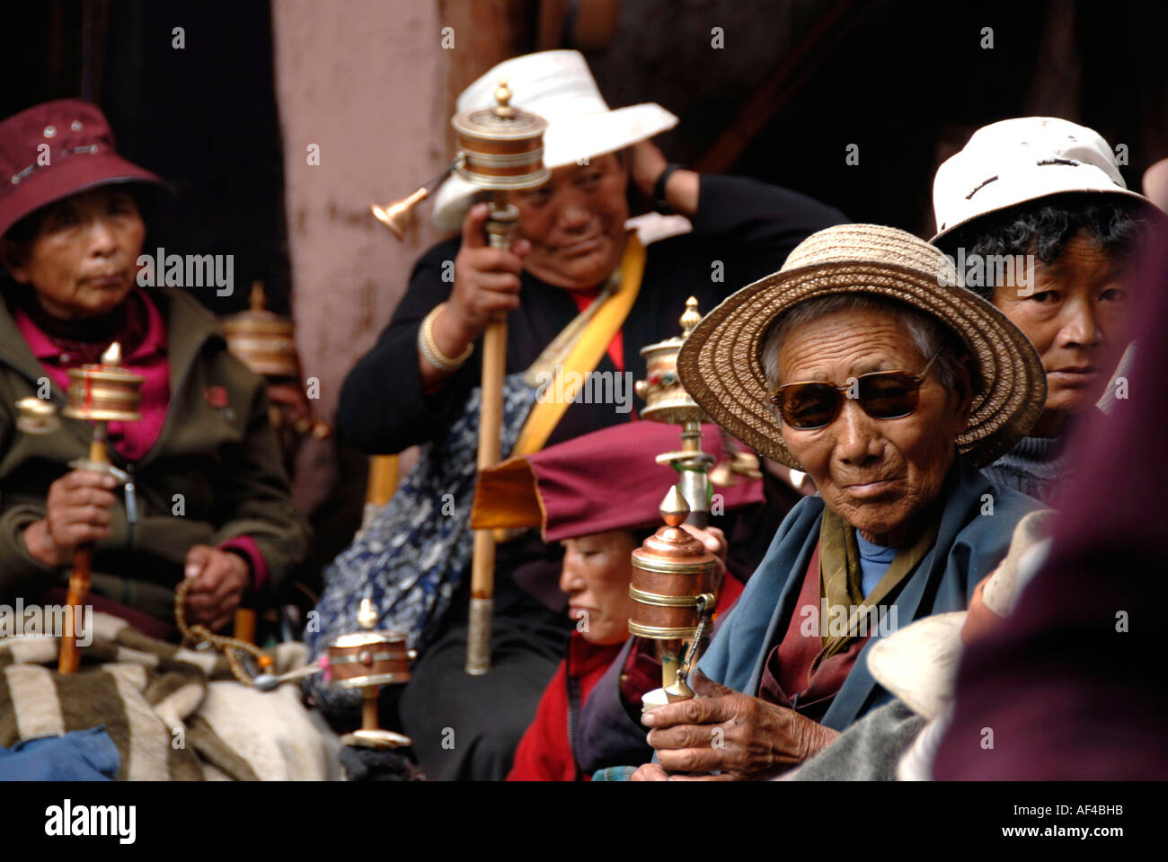 Old Tibetan pilgrims sit in a backyard with prayer wheels Lhasa Tibet ...