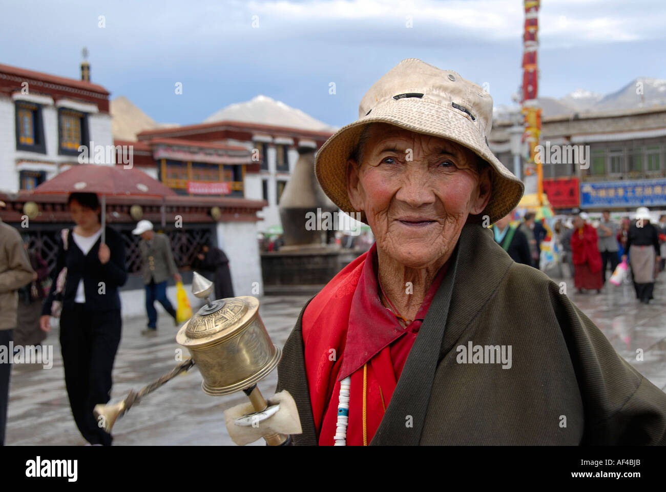 Tibetan pilgrim woman with prayer wheel at the Kora at Jokhang Temple ...