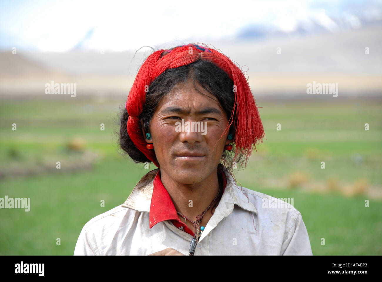 Portrait young Tibetan man with red head decoration near Old Tingri ...