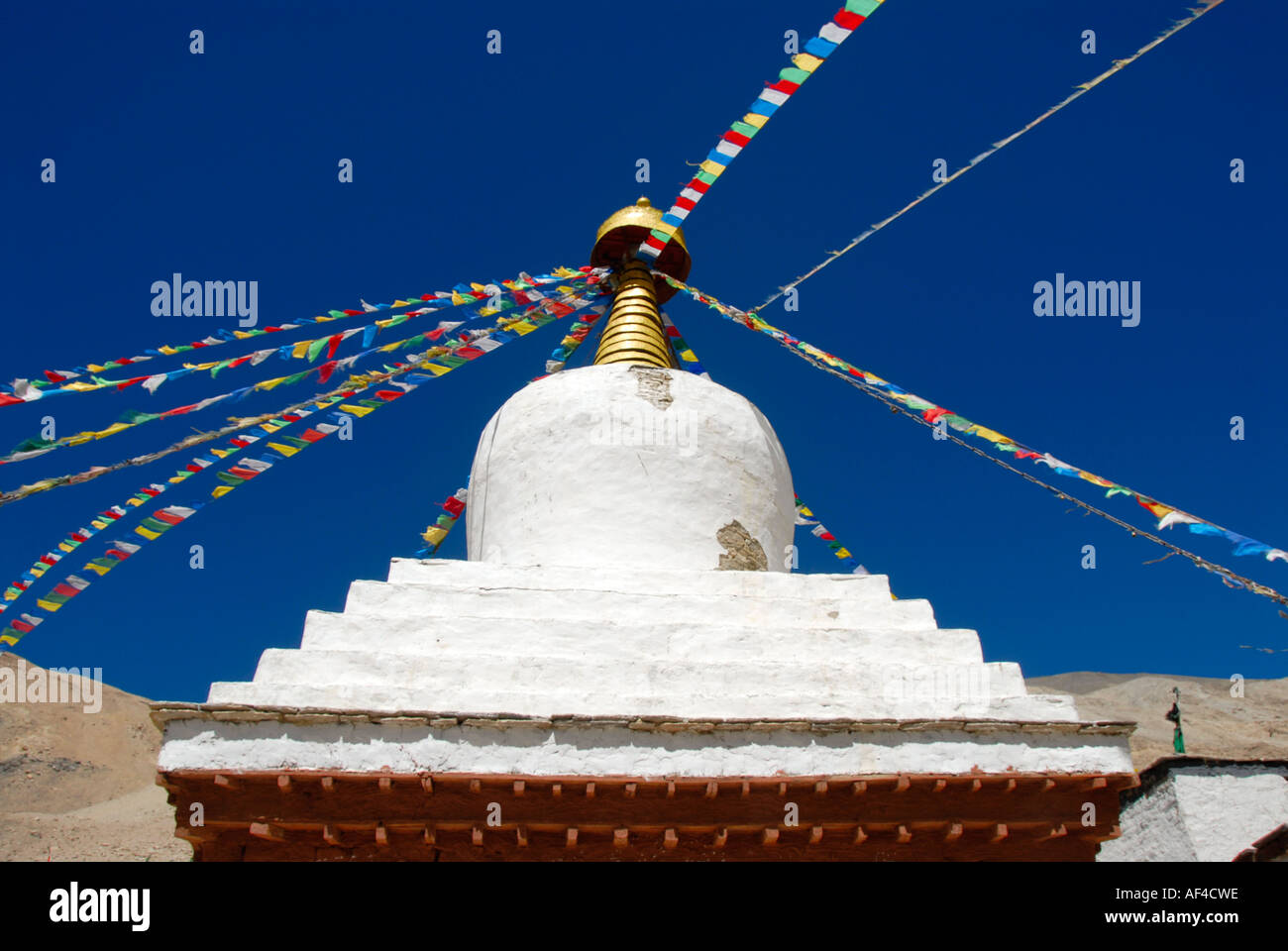 White stupa with colourful prayer flags against the blue sky Rongbuk ...