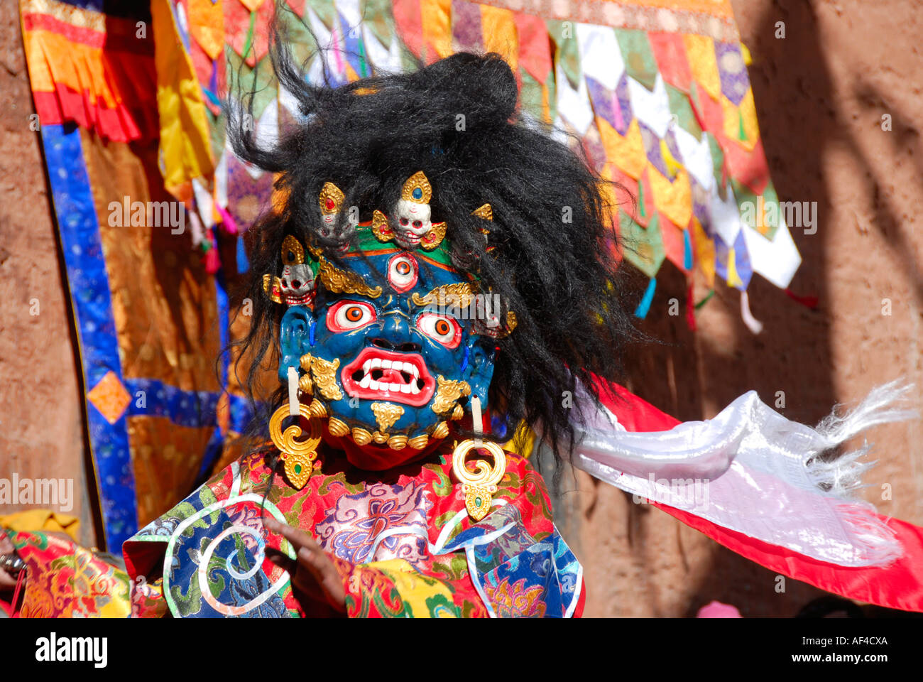 Monk wears fearful and blue mask of a demon at festival in colourful ...