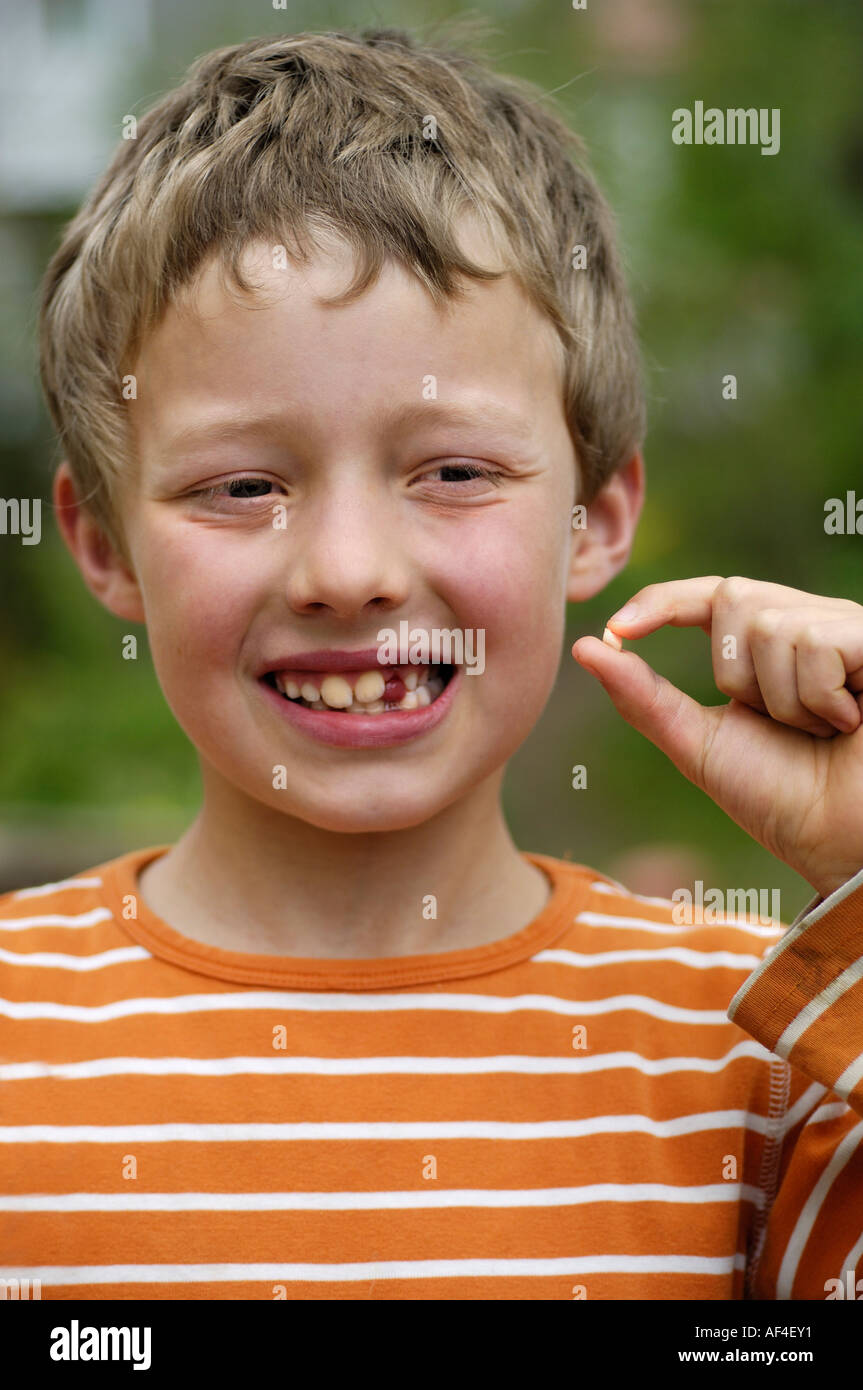 8 year old boy proudly holds his freshly fallen out milk tooth Stock ...