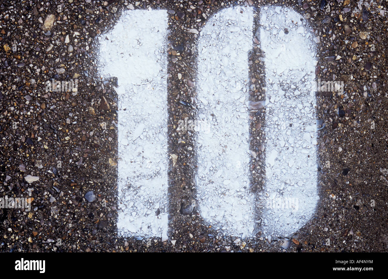Close up of white painted stencilled number 10 on rough concrete wall ...