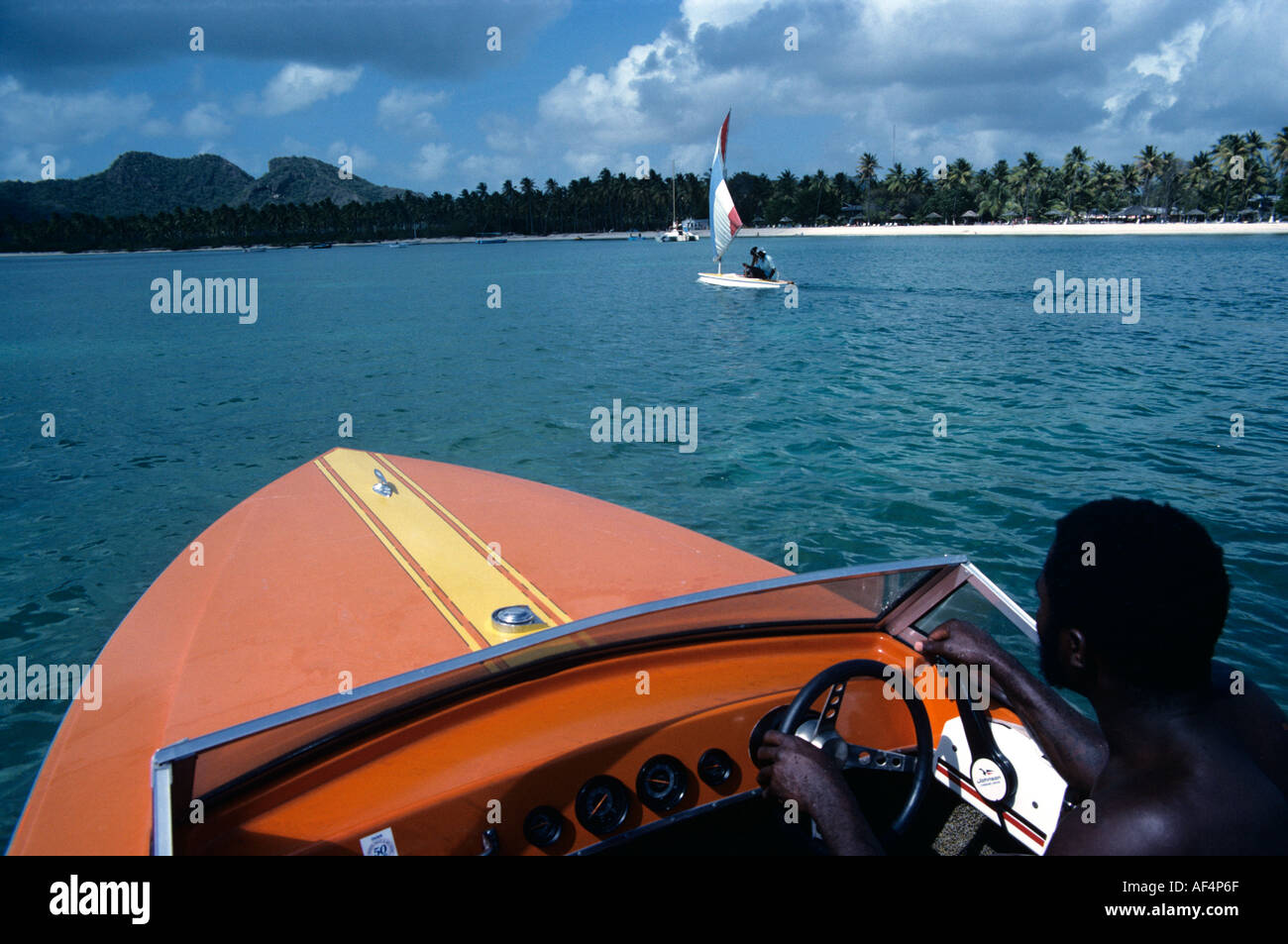 View from the cockpit of a red speedboat with local man at wheel small ...