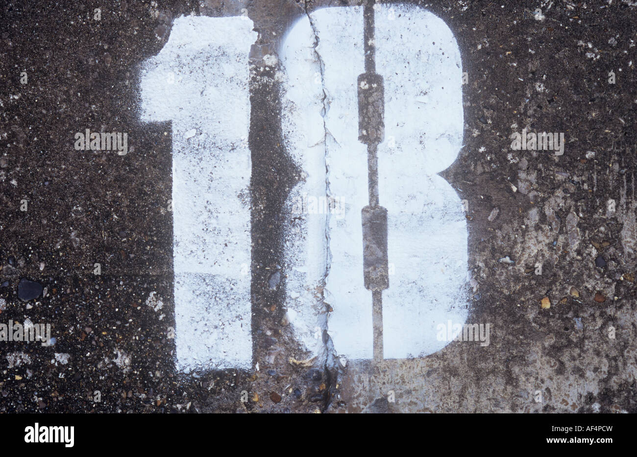 Close up of white painted stencilled number 18 on rough concrete wall ...